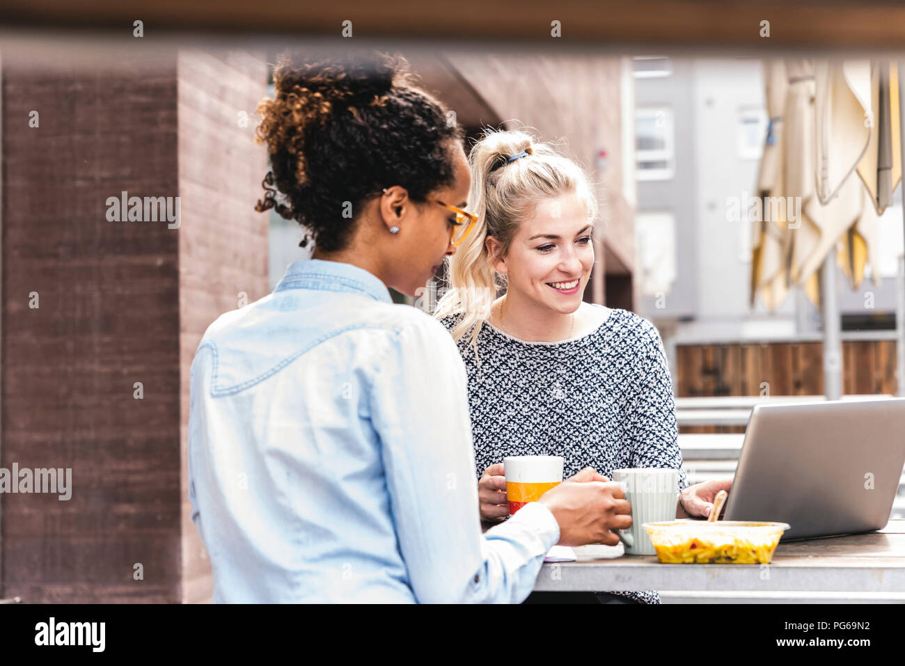 Young colleagues sitting outdoors, working together, having lunch Stock ...