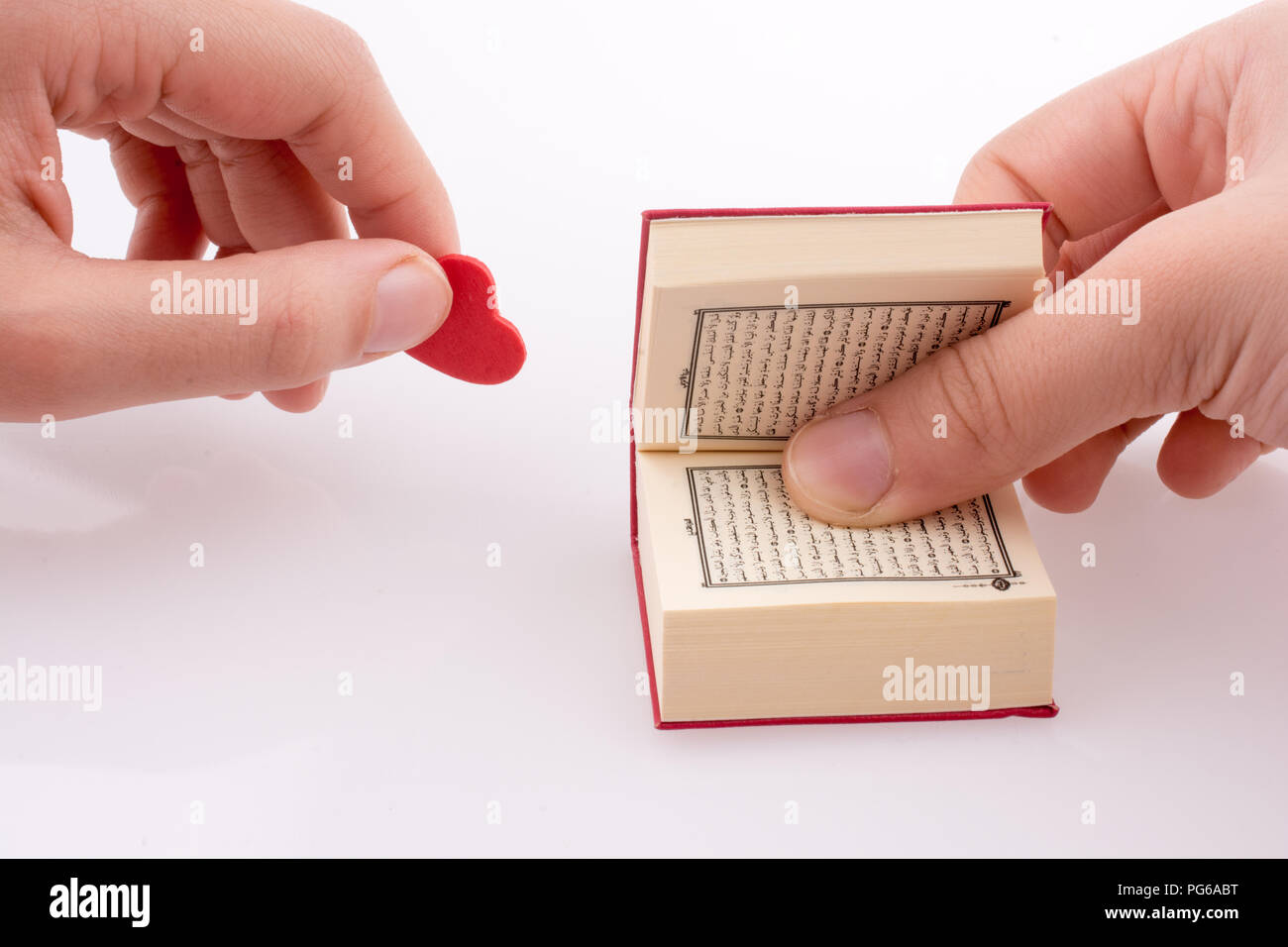 Hand holding The Holy Quran with a heart on a white background Stock ...