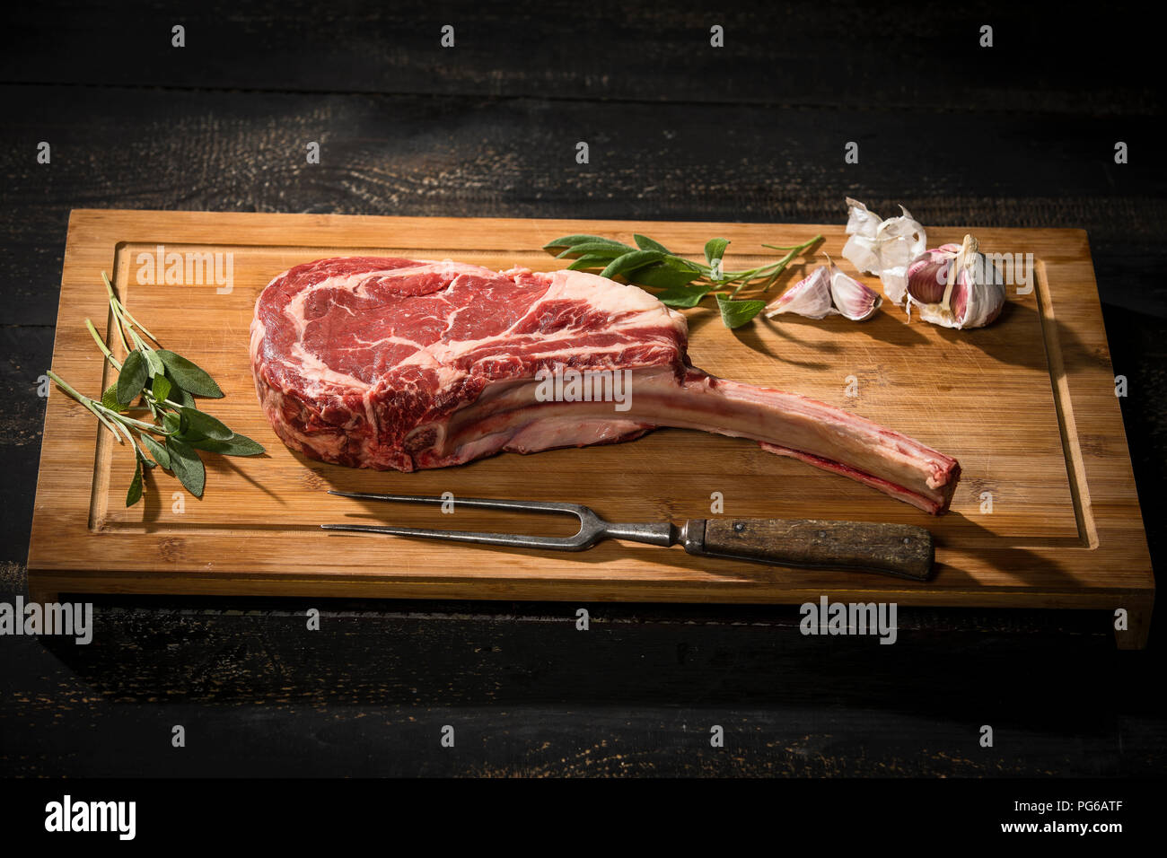 Raw tomahawk steak, garlic and herbs Stock Photo - Alamy