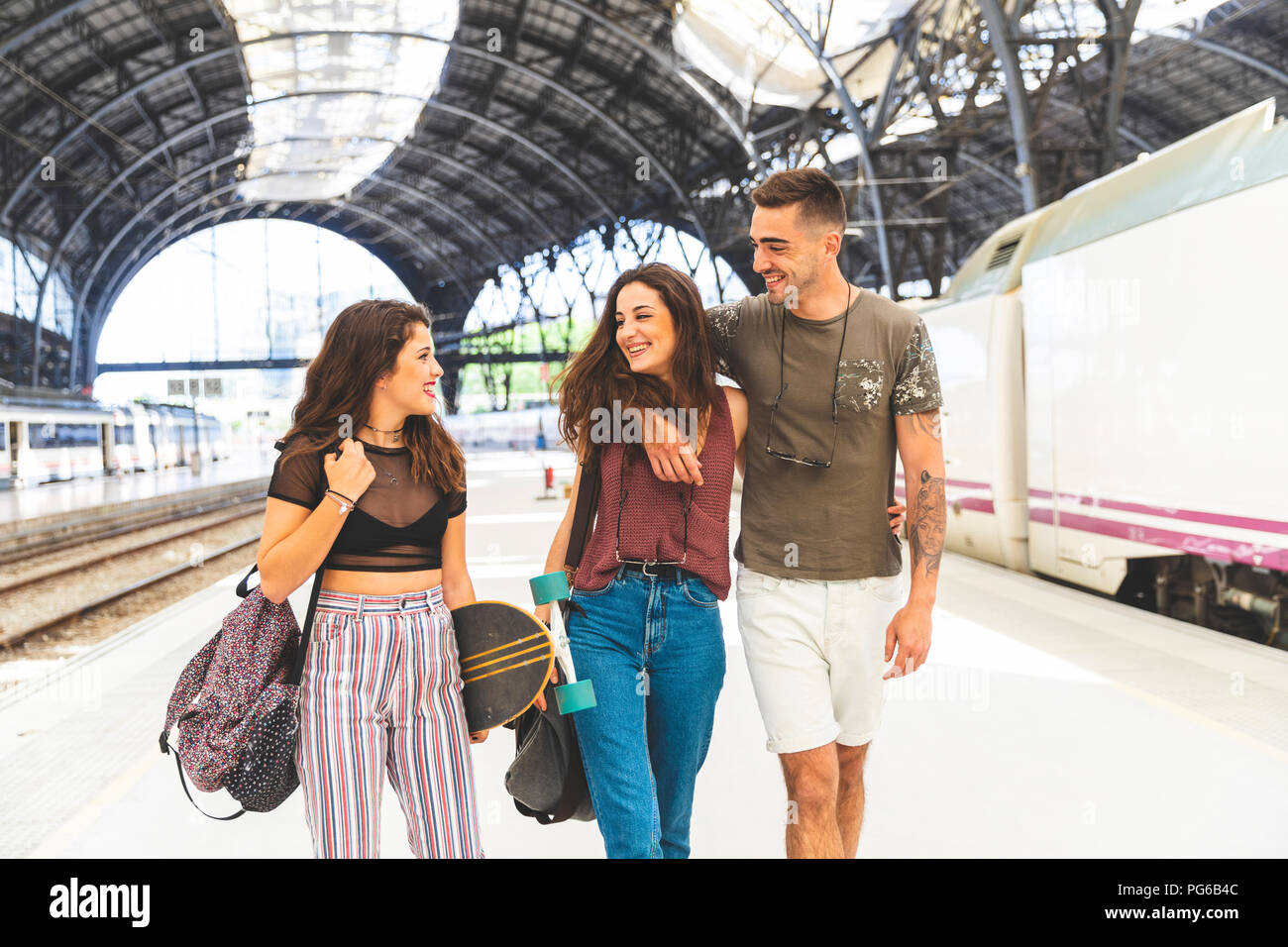 Happy friends on train station platform Stock Photo - Alamy