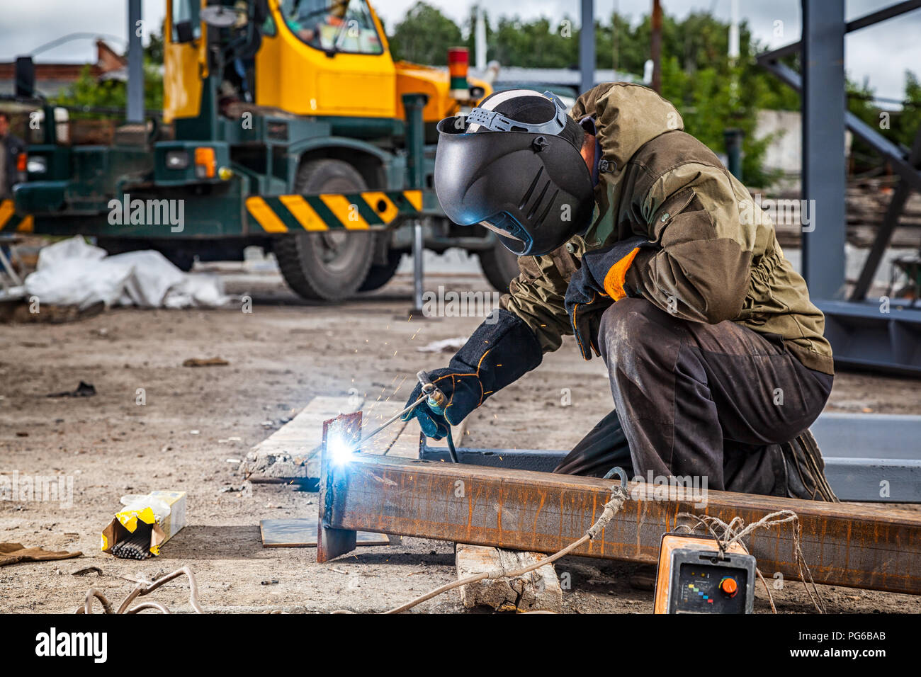 A young man welder in brown uniform, welding mask and welders leathers ...