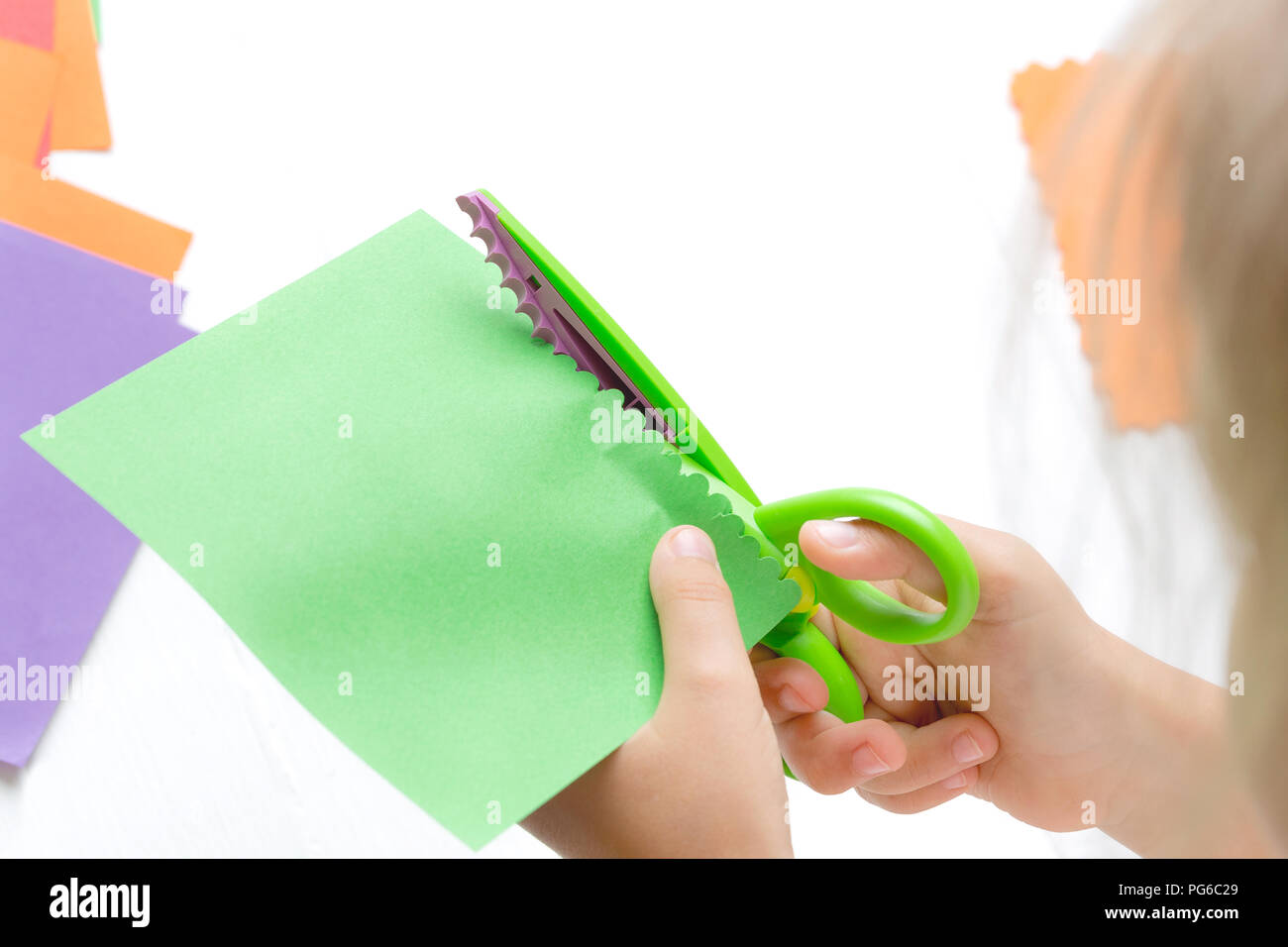 Children's hands cut out colored paper with figured scissors ...