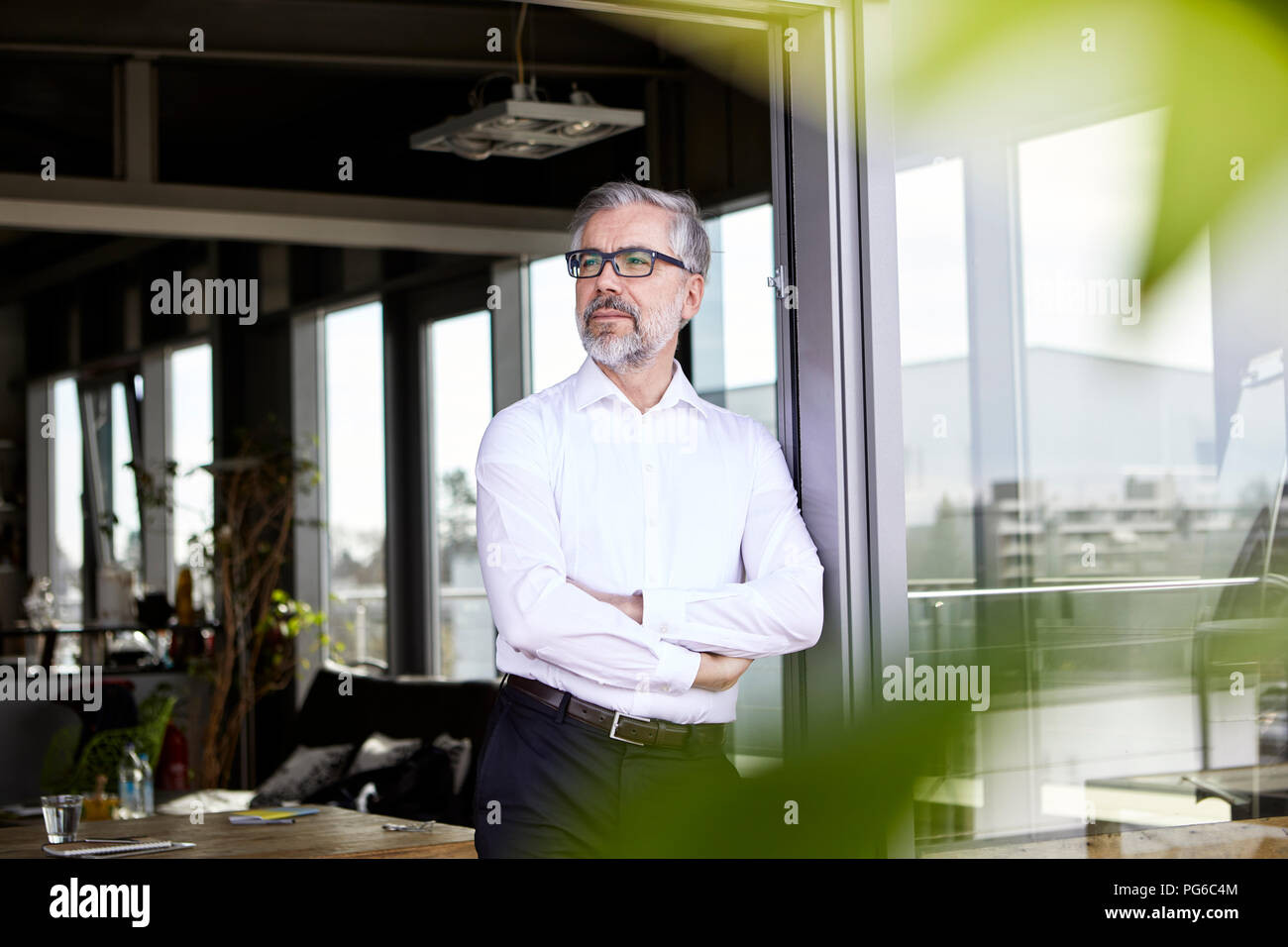 Businessman standing at French door thinking Stock Photo - Alamy
