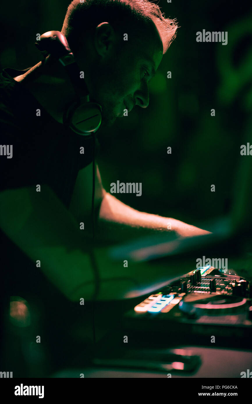 Club, disco DJ playing and mixing music for crowd of happy people ...