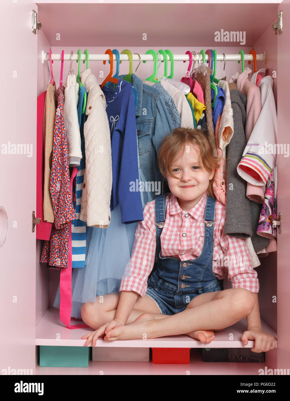 A little girl is sitting in a wardrobe with a children's department ...
