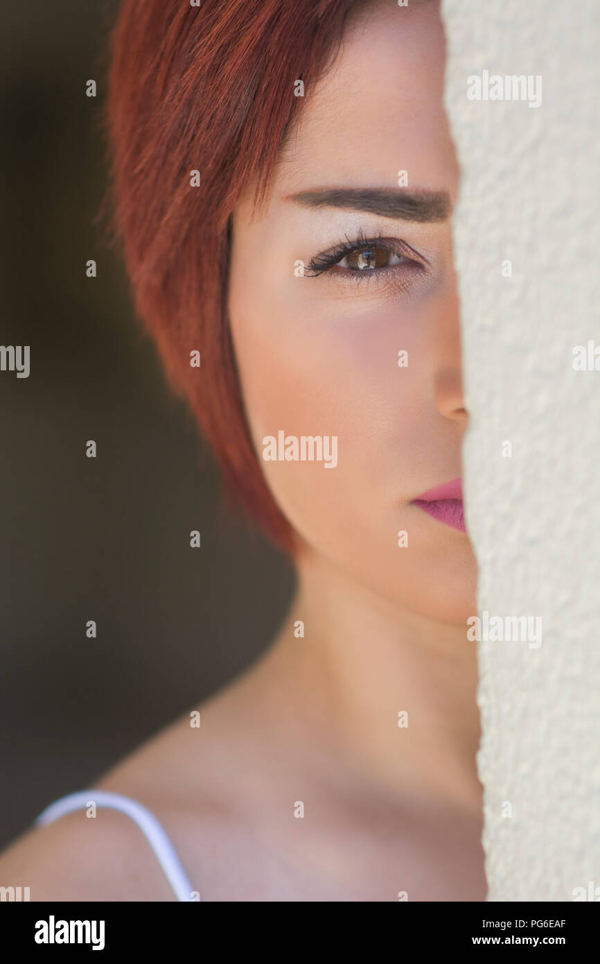 Scared young woman hiding behind wall Stock Photo - Alamy