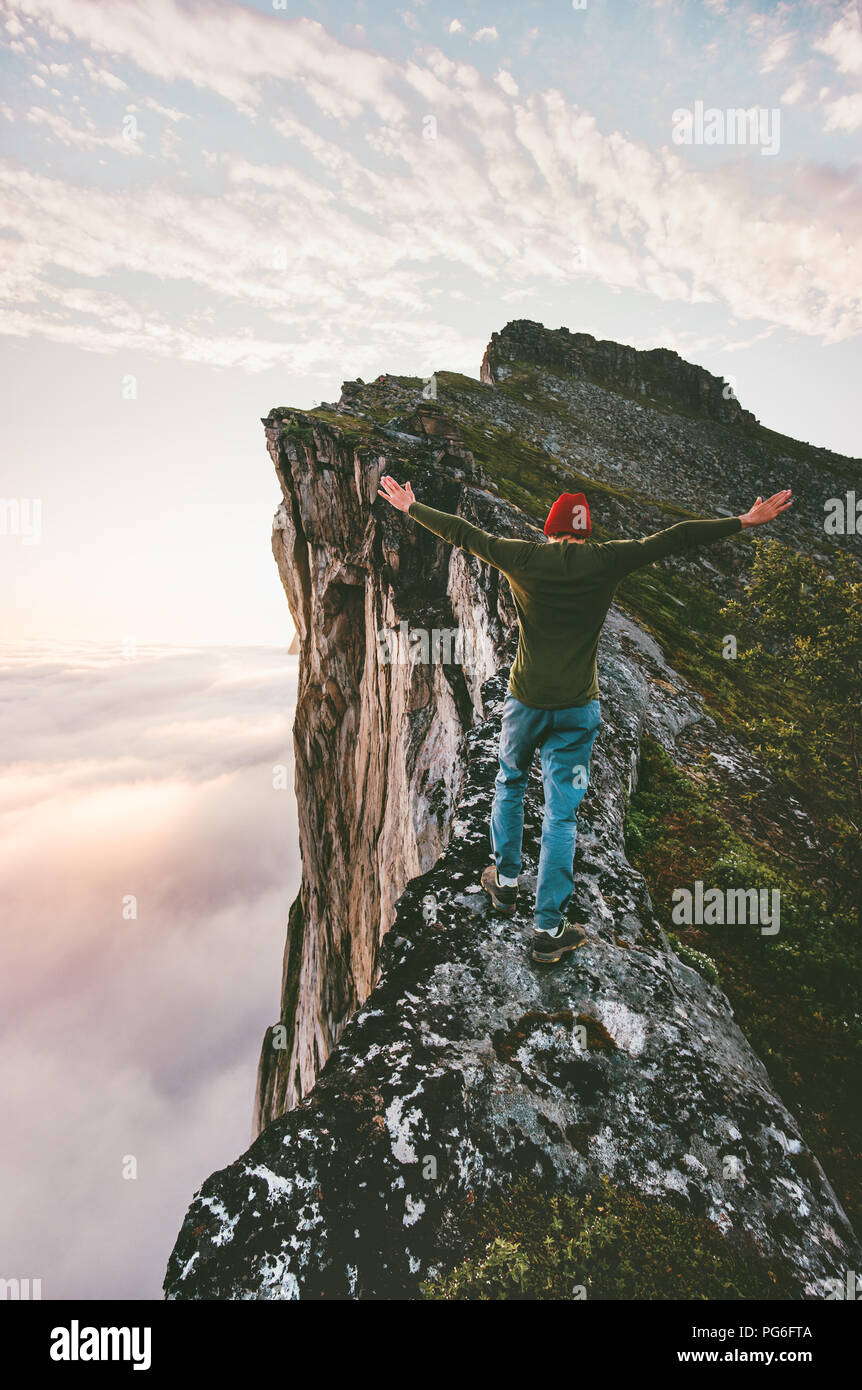 Adventurer man on the edge mountain ridge above clouds travel extreme ...