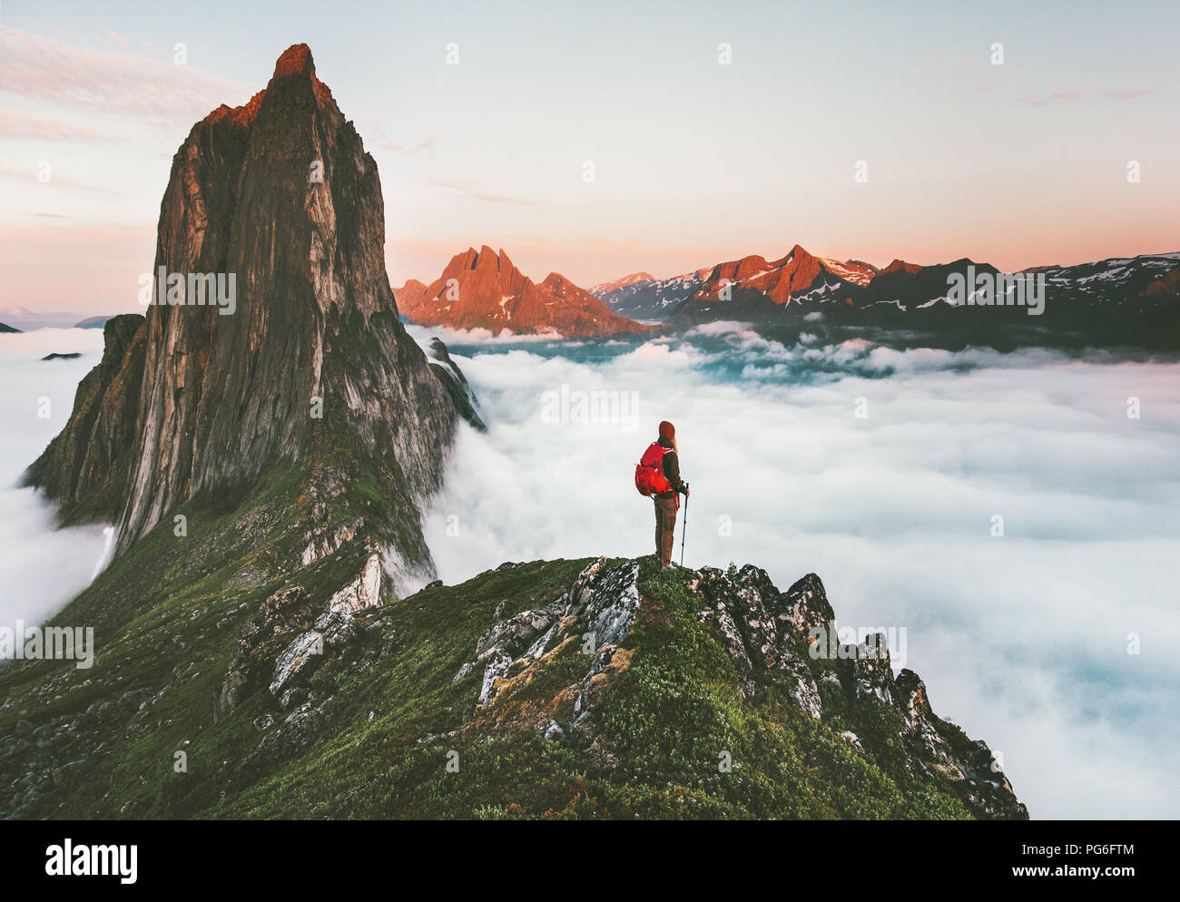 Traveler on cliff over clouds exploring sunset Segla mountain alone ...