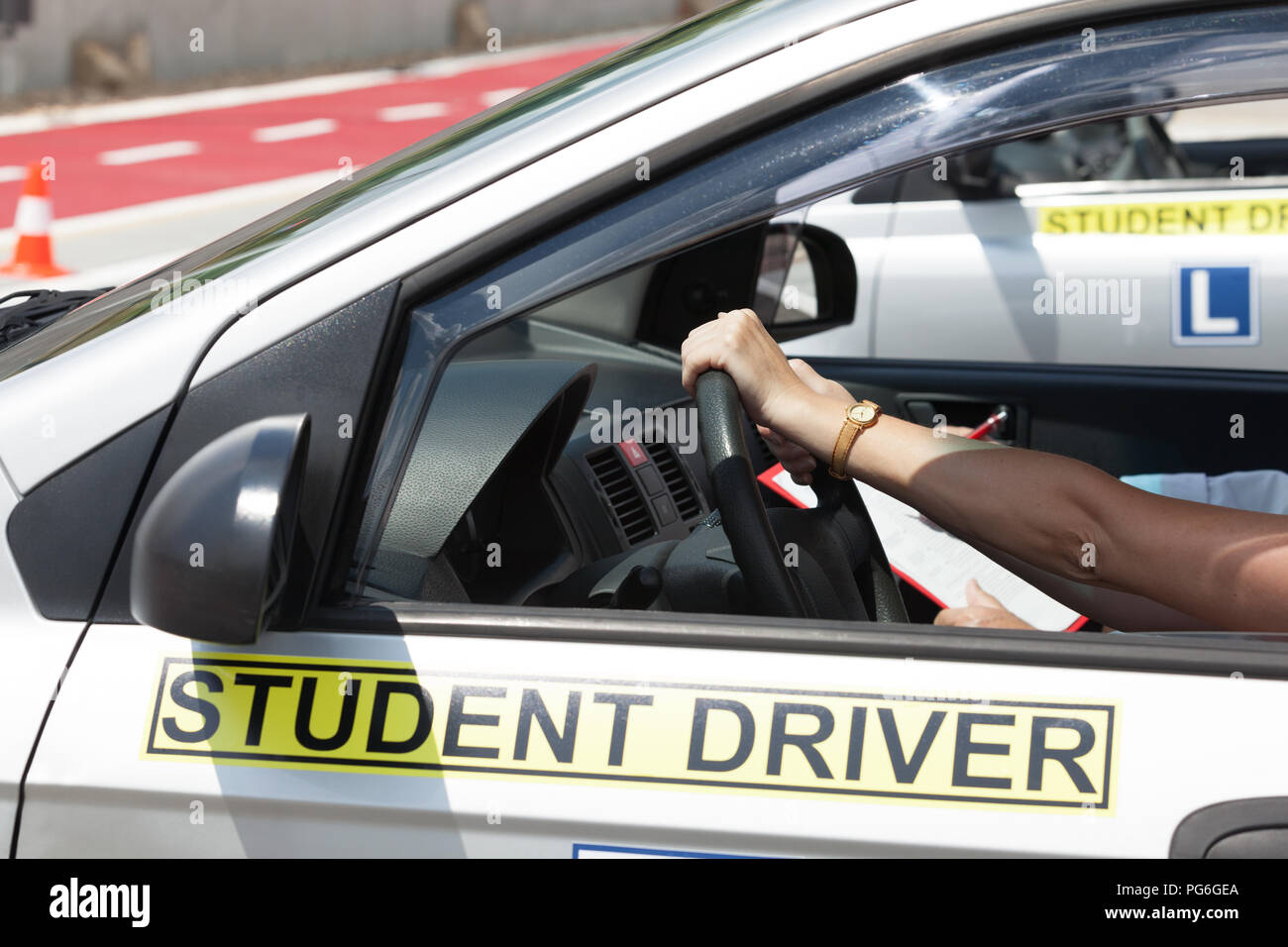 A woman, hands on the steering wheel, learning to drive car at driving ...