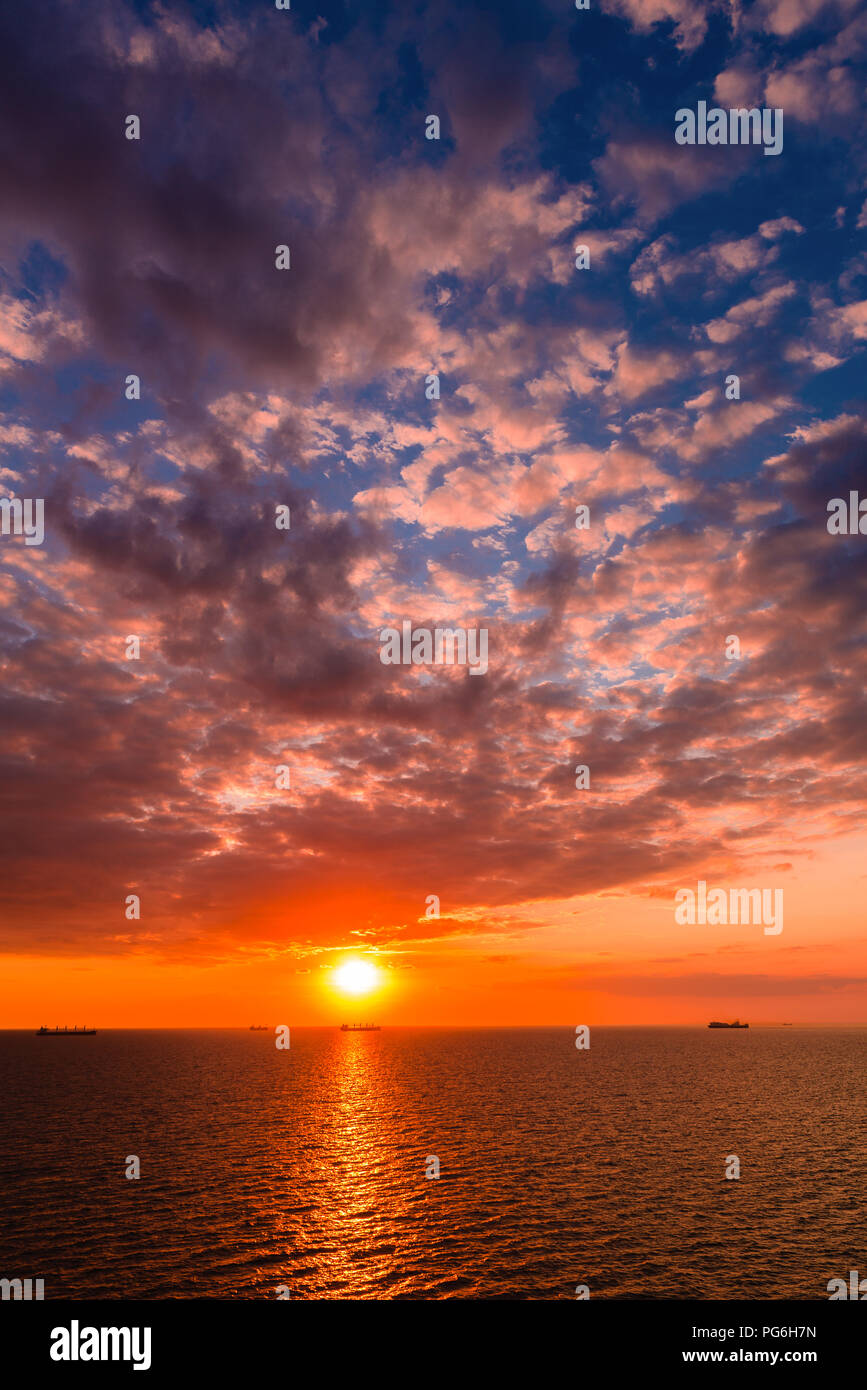 Ocean lane, cargo ships, coloful sunset and impressive evening clouds ...