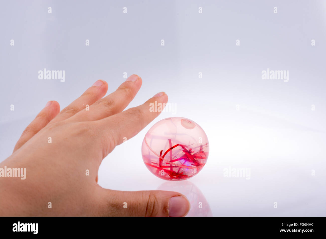Red transparent ball and hand on white background Stock Photo - Alamy