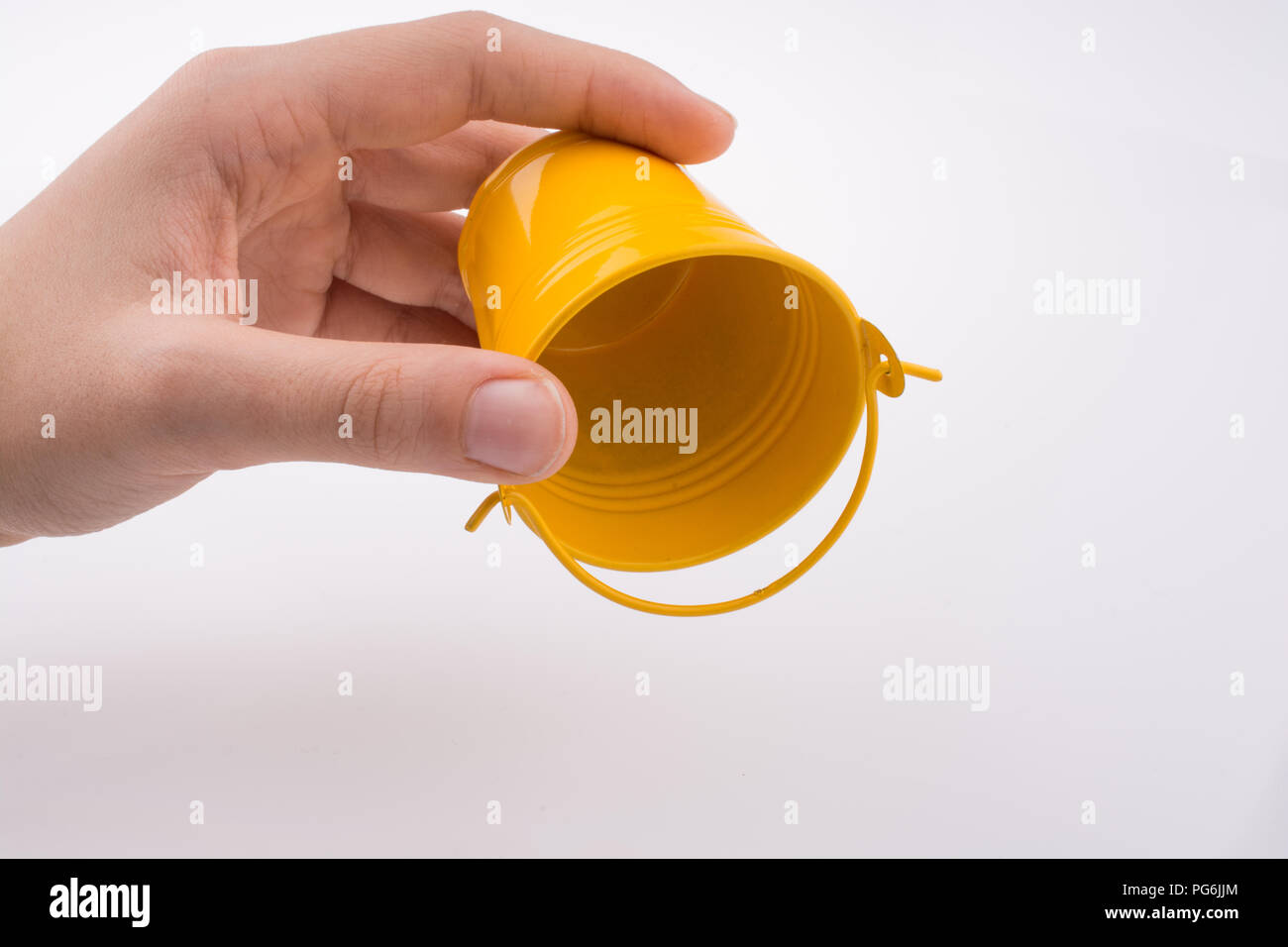 Hand holding a yellow bucket on a white background Stock Photo - Alamy