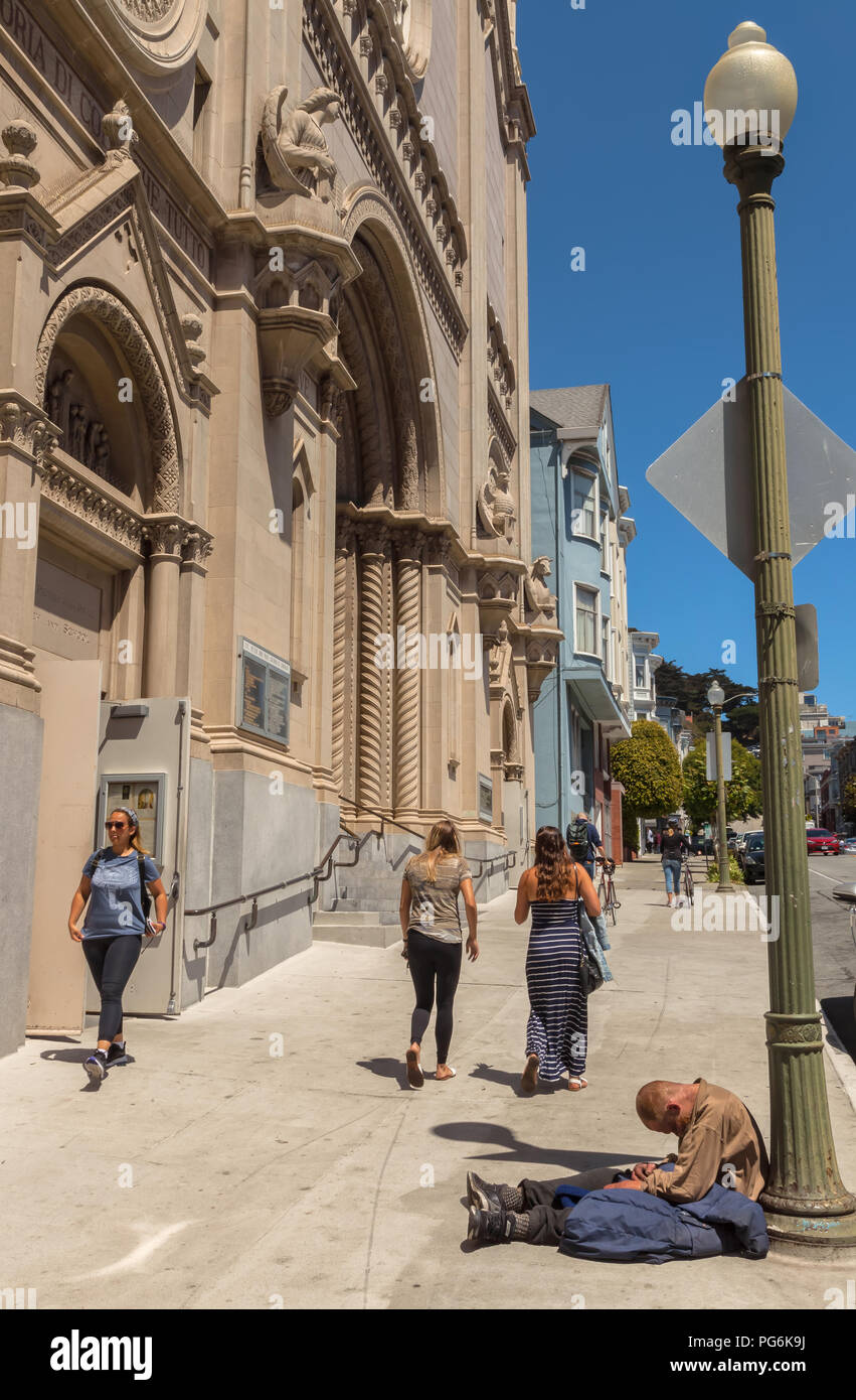 Homeless man was sleeping on the sidewalk by the light pole, with ...