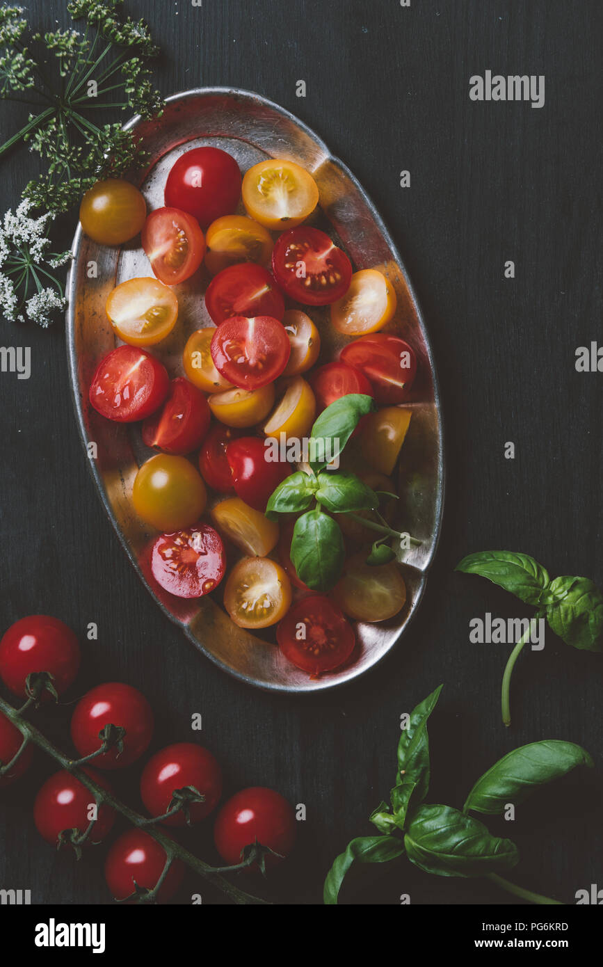 top view of cutted red and yellow cherry tomatoes in metal plate with ...