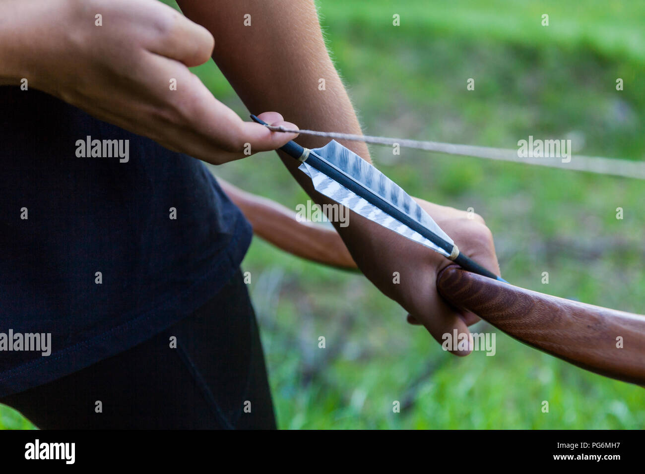 Hand of archeress straining bow, close-up Stock Photo - Alamy