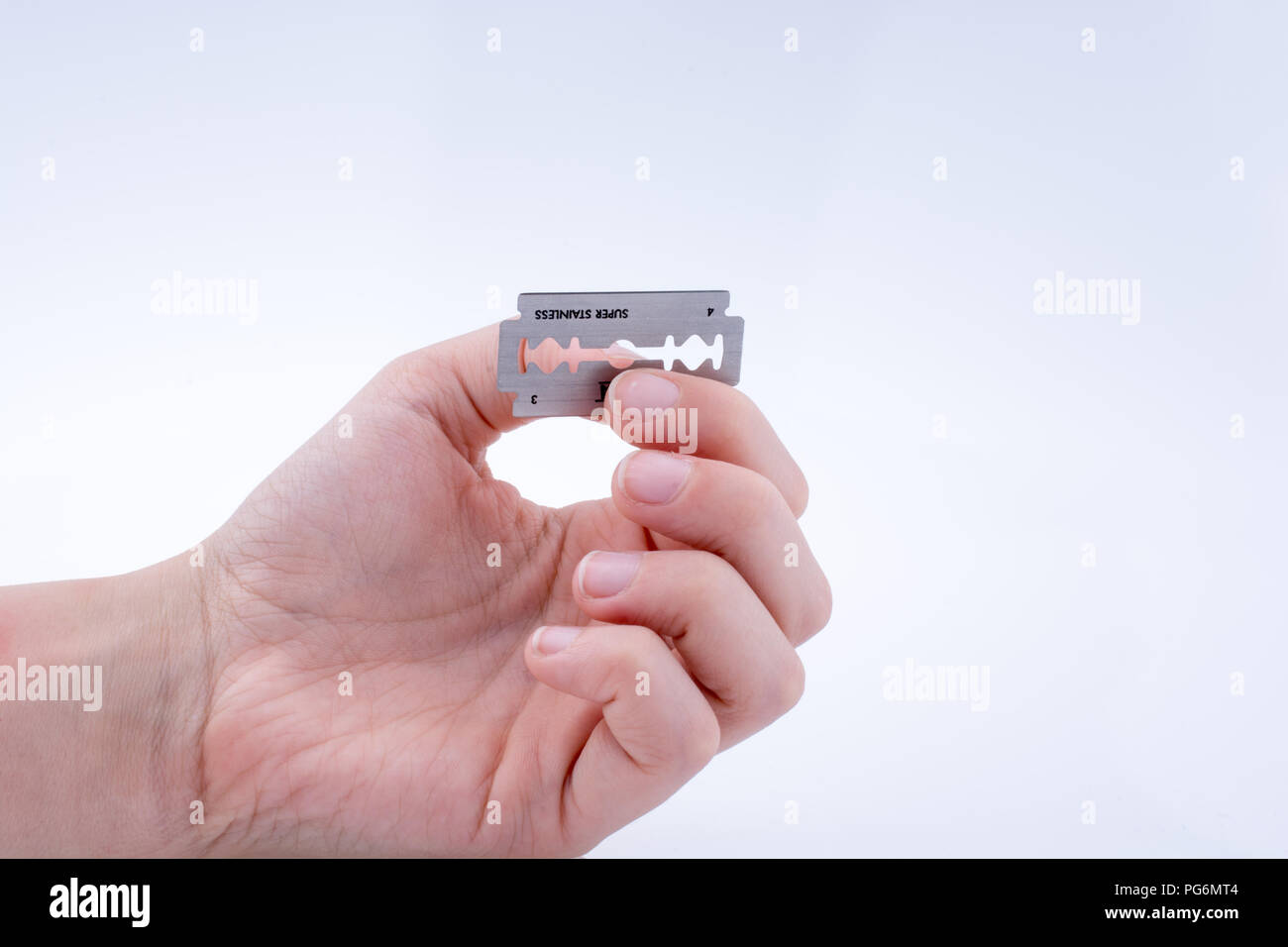 Hand holding a razor blade on a white background Stock Photo - Alamy