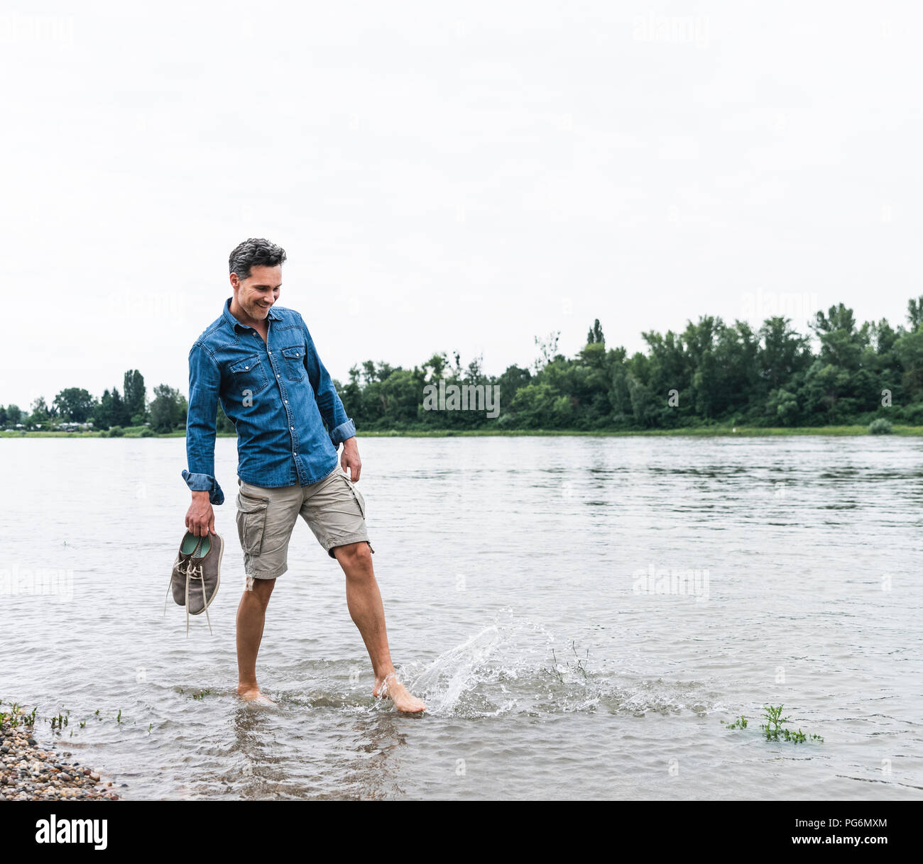 Smiling man splashing water in a river Stock Photo - Alamy