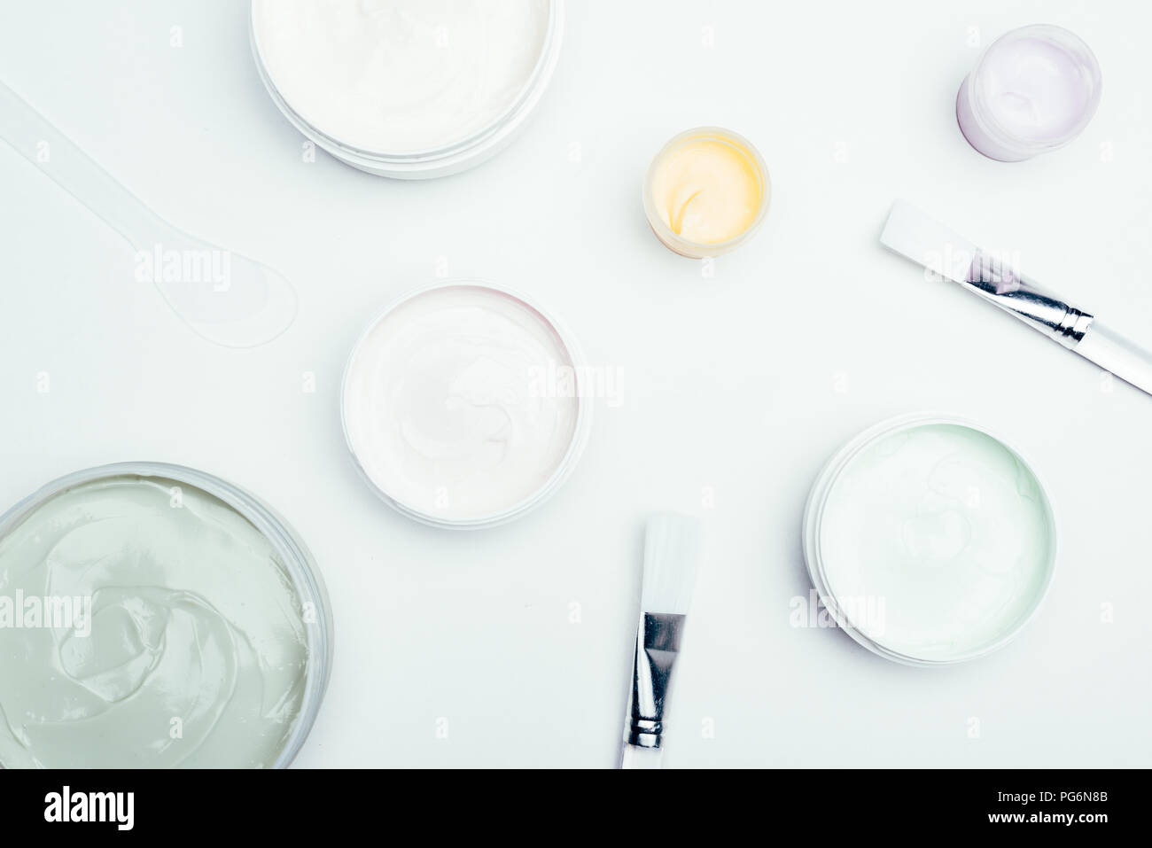 flat lay with different clay masks in containers and brushes isolated ...