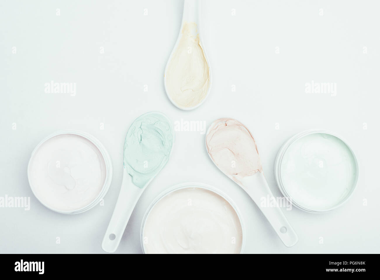 flat lay with various colorful clay masks in containers and spoons ...