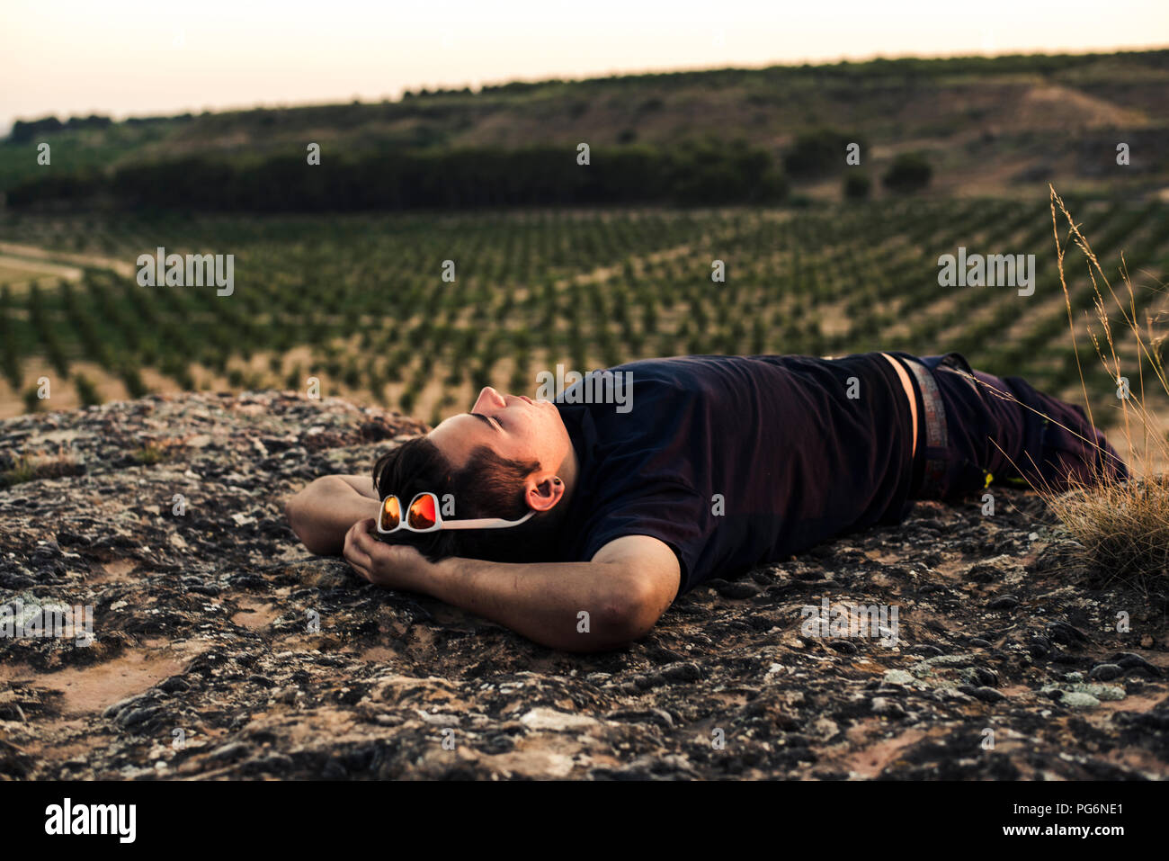 Young man lying on rock, sleeping Stock Photo - Alamy