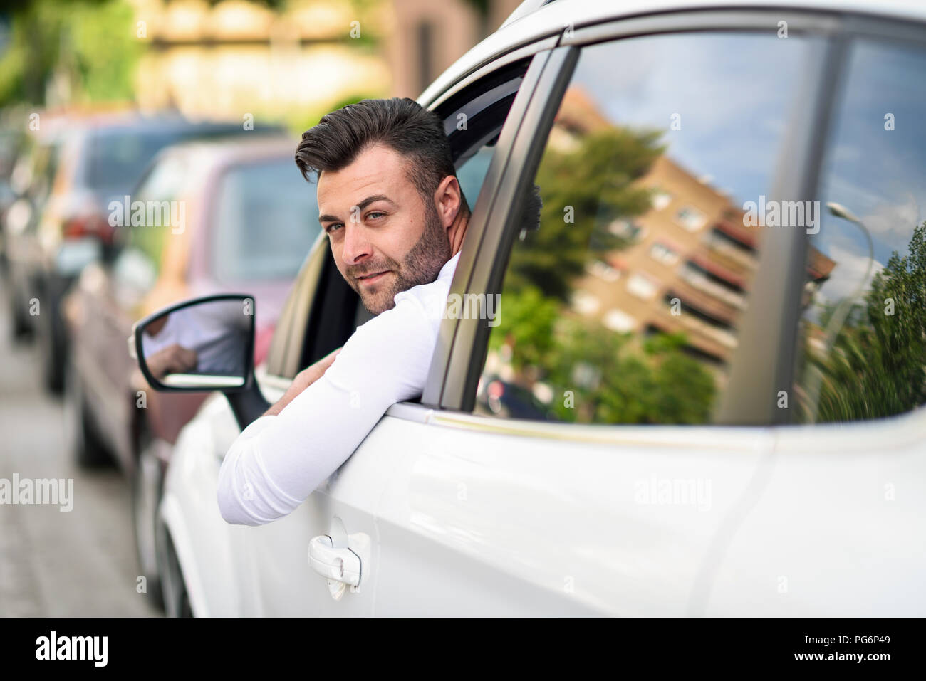 Man leaning out the window of his car in the city Stock Photo - Alamy