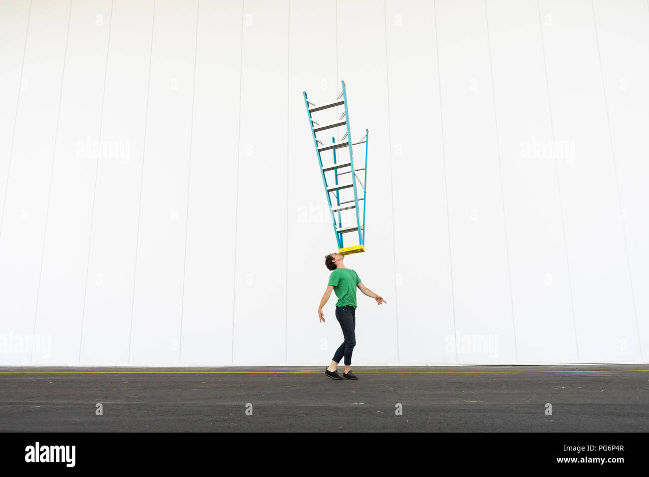 Acrobat balancing ladder on his face Stock Photo - Alamy