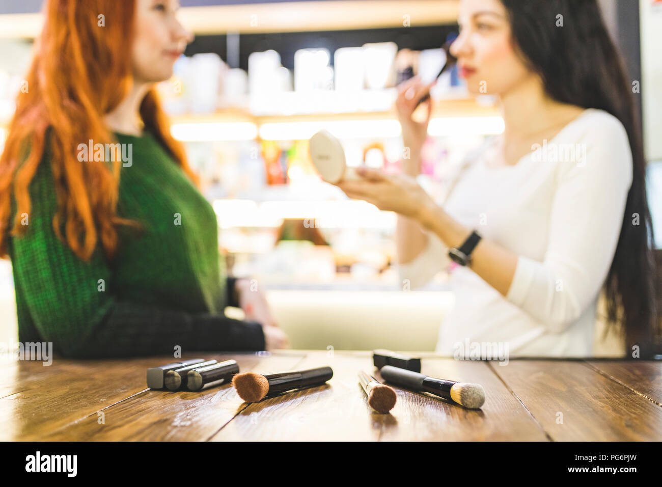 Two women in a cosmetics shop trying make up Stock Photo - Alamy