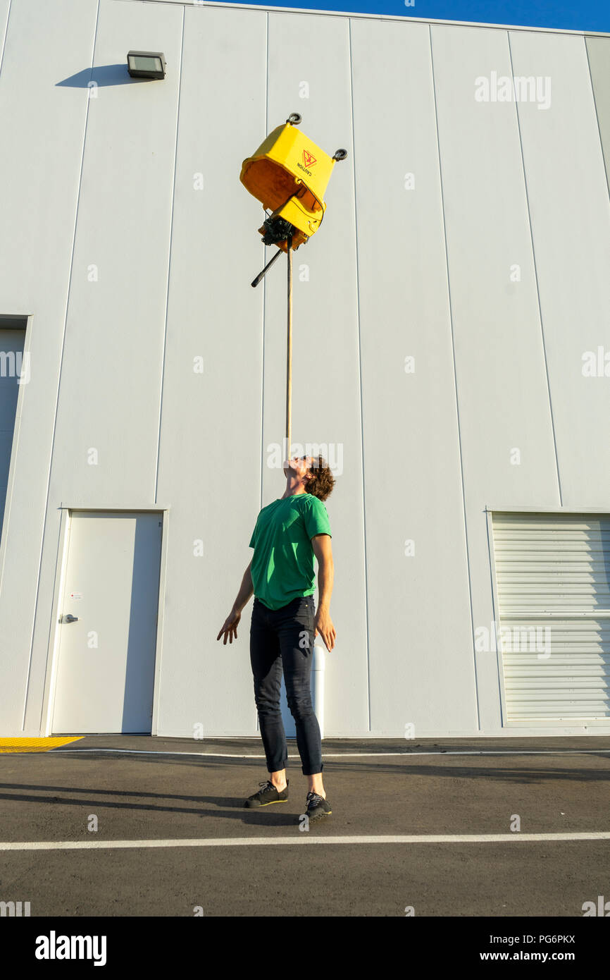 Acrobat balancing bucket on mop on his chin Stock Photo - Alamy