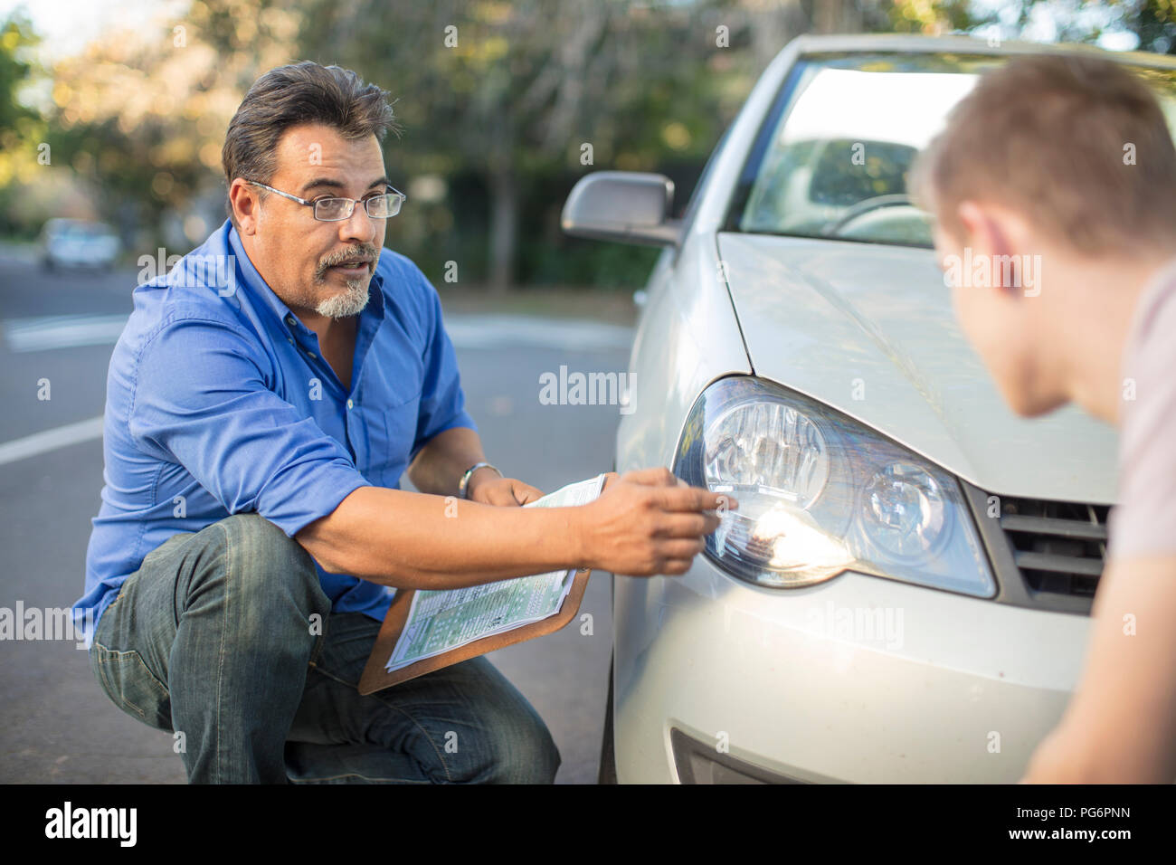 Learner driver with instructor checking headlight of a car Stock Photo ...