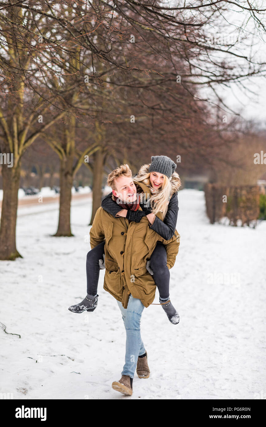 Young man giving his girlfriend a piggyback ride in winter Stock Photo ...
