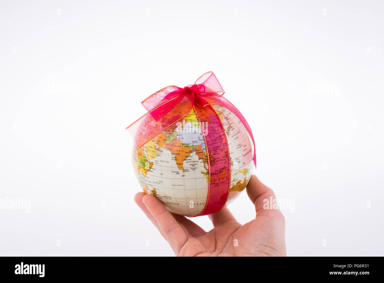 Globe tied with red ribbon on a white background Stock Photo - Alamy
