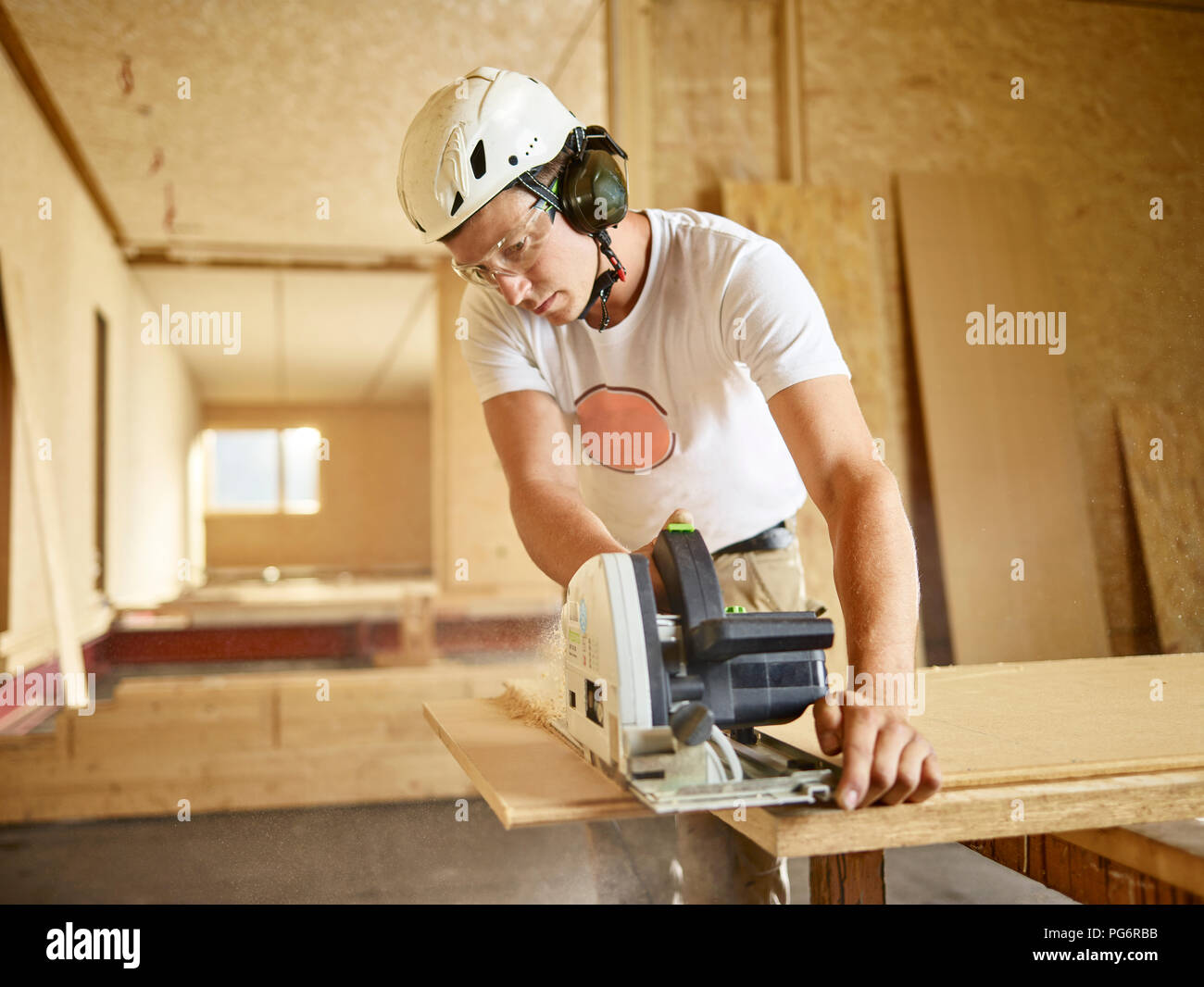Worker with helmet sawing wood with circular saw Stock Photo - Alamy
