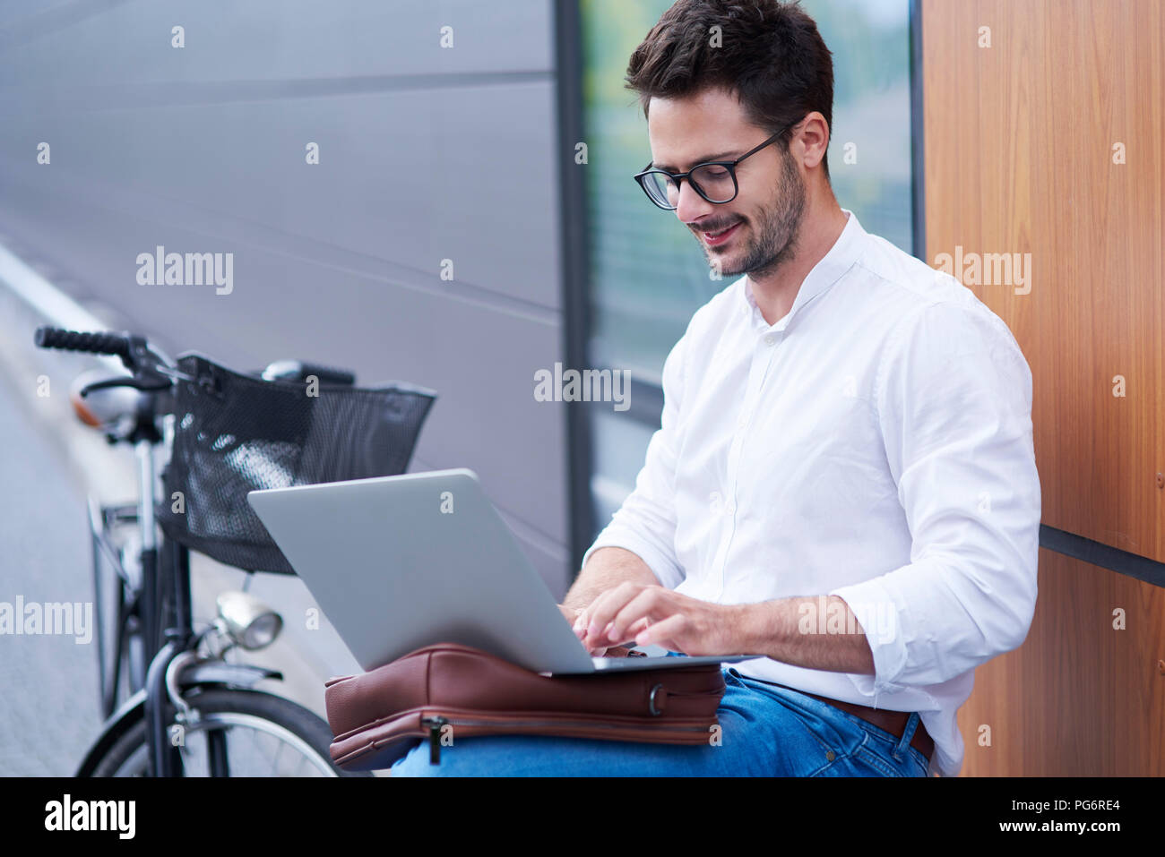 Businessman with bicycle using laptop outdoors Stock Photo - Alamy