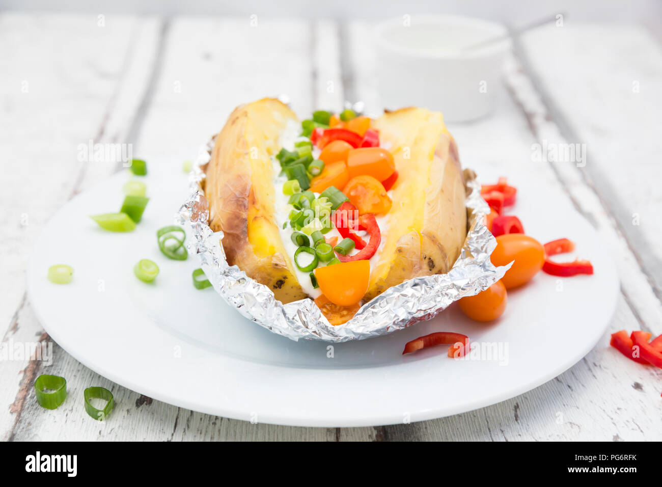 Baked patato with curd and chives, bell pepper, tomato and spring ...