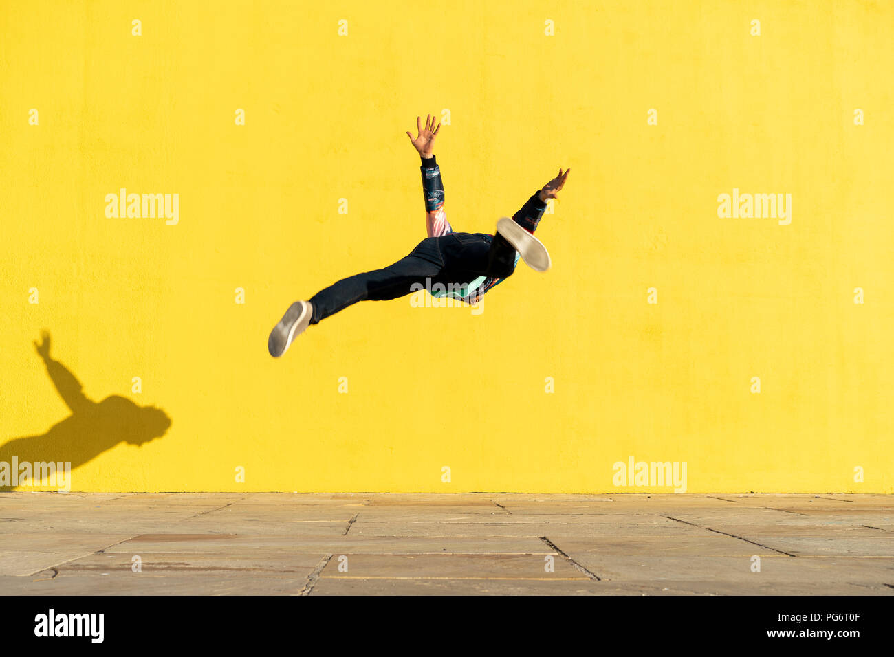 Acrobat jumping somersaults in front of yellow wall Stock Photo - Alamy