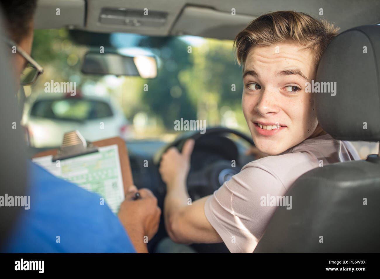 Learner driver with instructor in car looking back Stock Photo - Alamy
