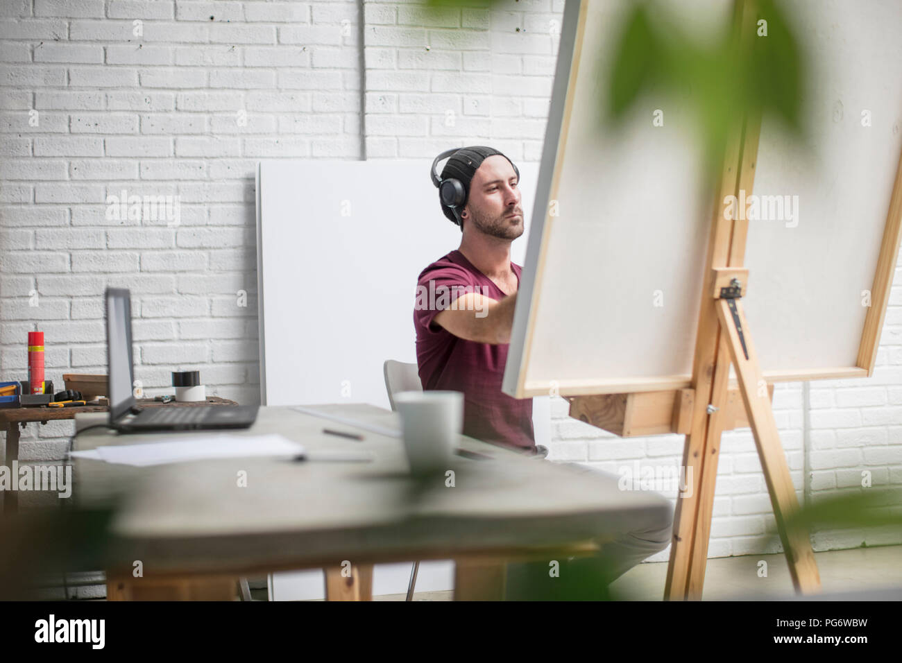 Artist wearing headphones drawing in studio Stock Photo - Alamy