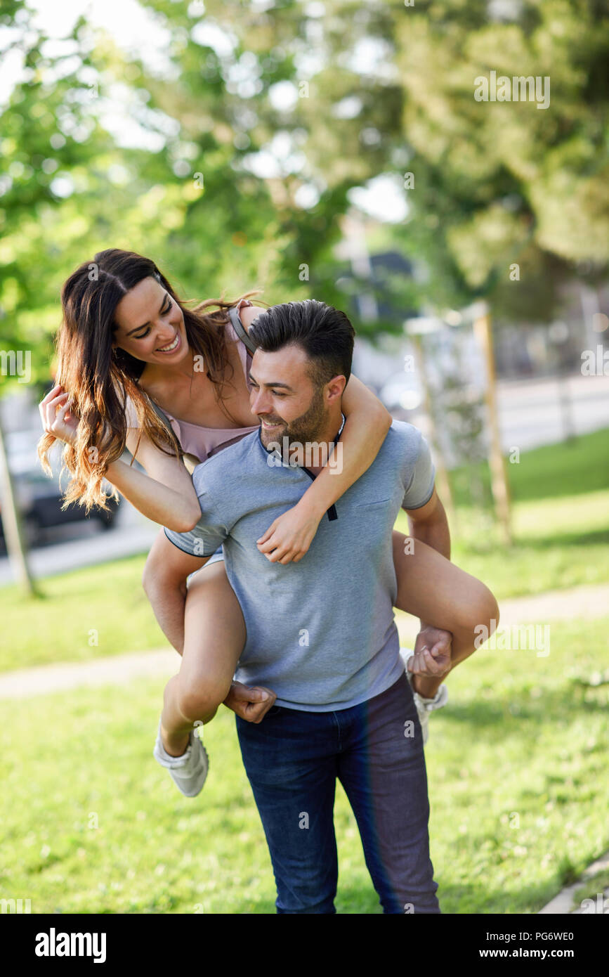 Happy man giving girlfriend a piggyback ride in park Stock Photo - Alamy