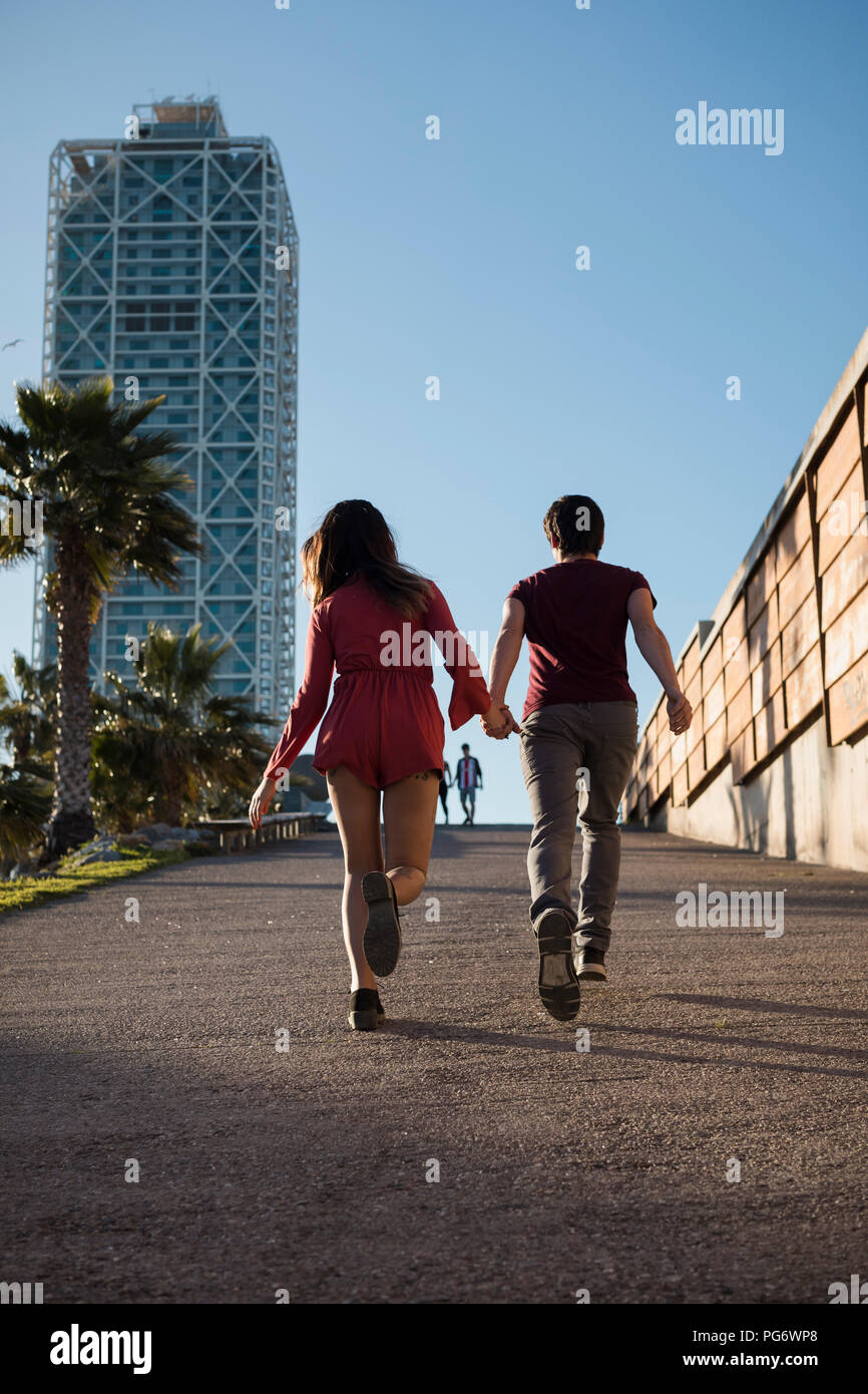 Spain, Barcelona, couple running hand in hand in the city Stock Photo ...