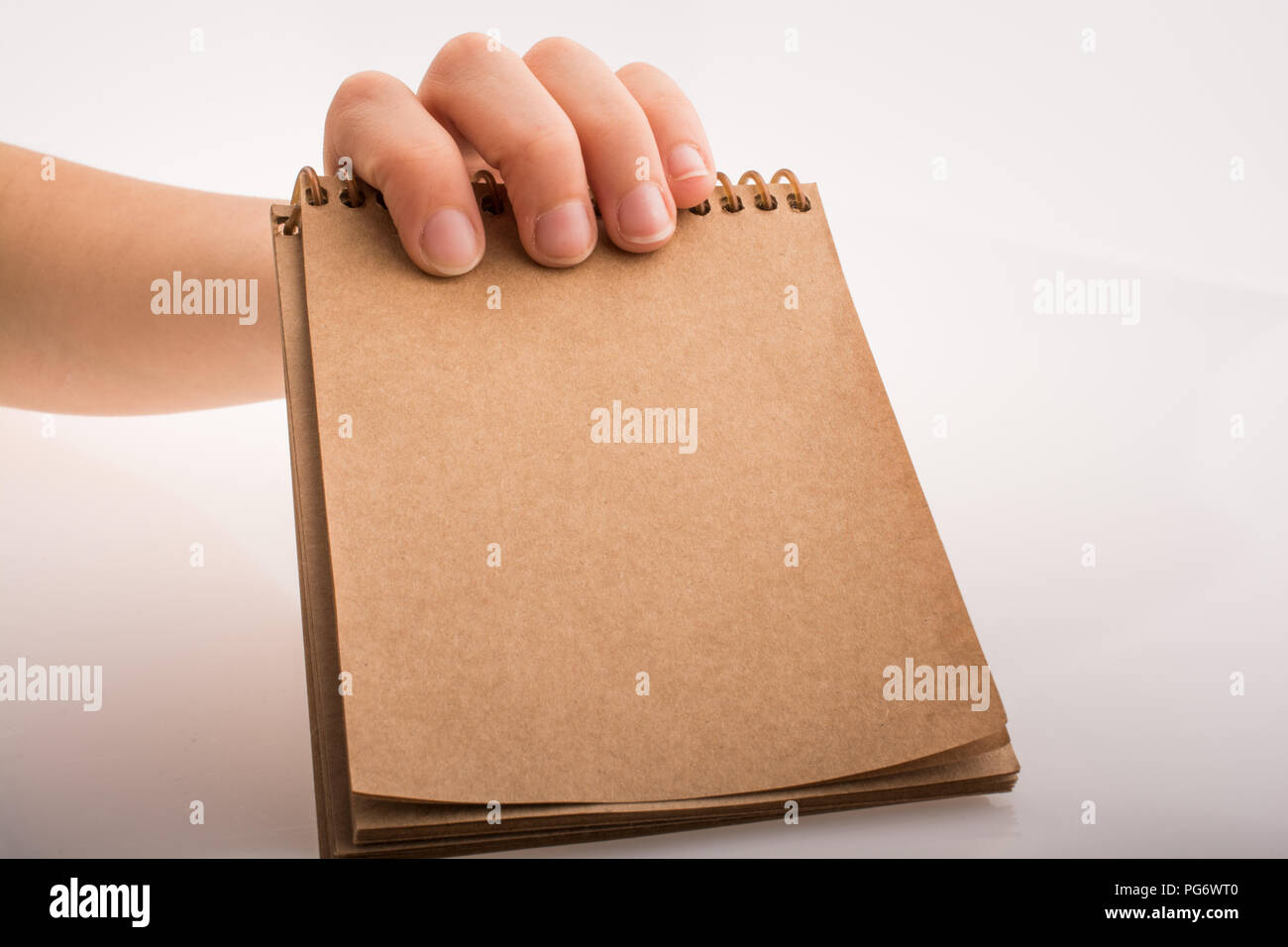 Hand holding a brown spiral notebook on a white background Stock Photo ...