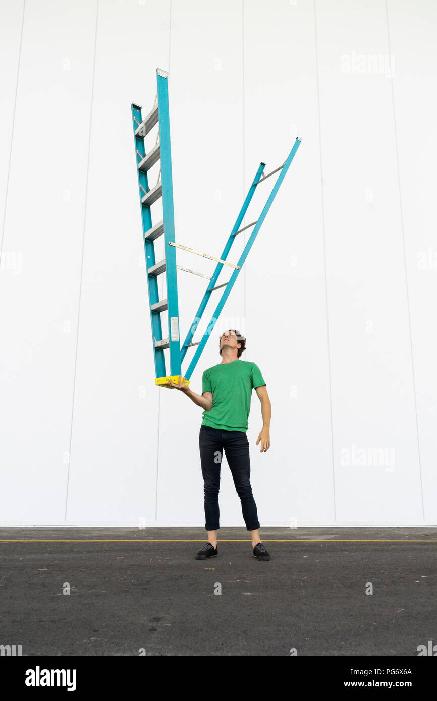 Acrobat balancing ladder upside down in his hand Stock Photo - Alamy