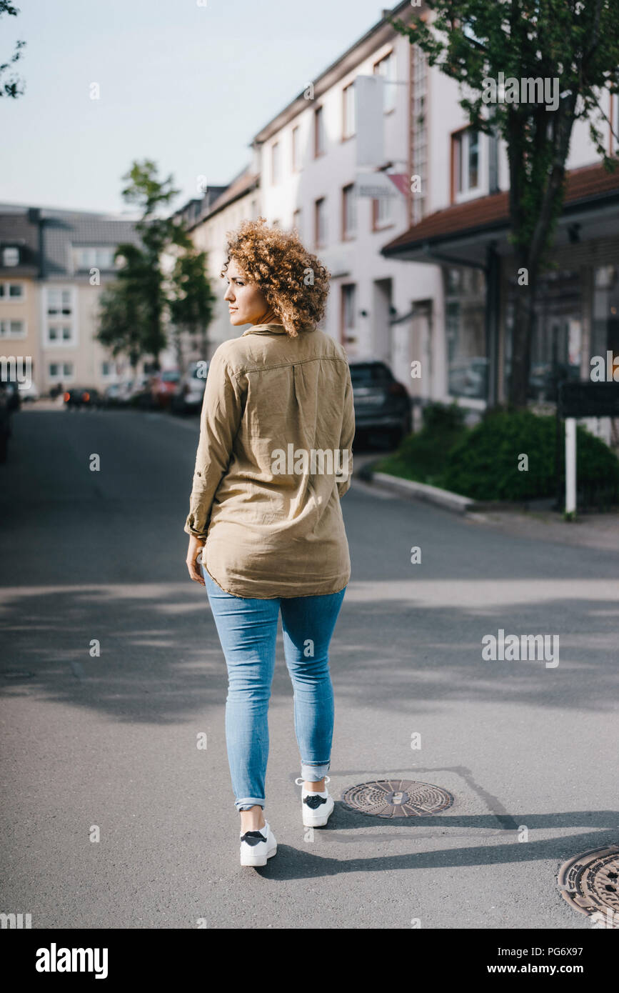 Dark haired woman walking away hi-res stock photography and images - Alamy