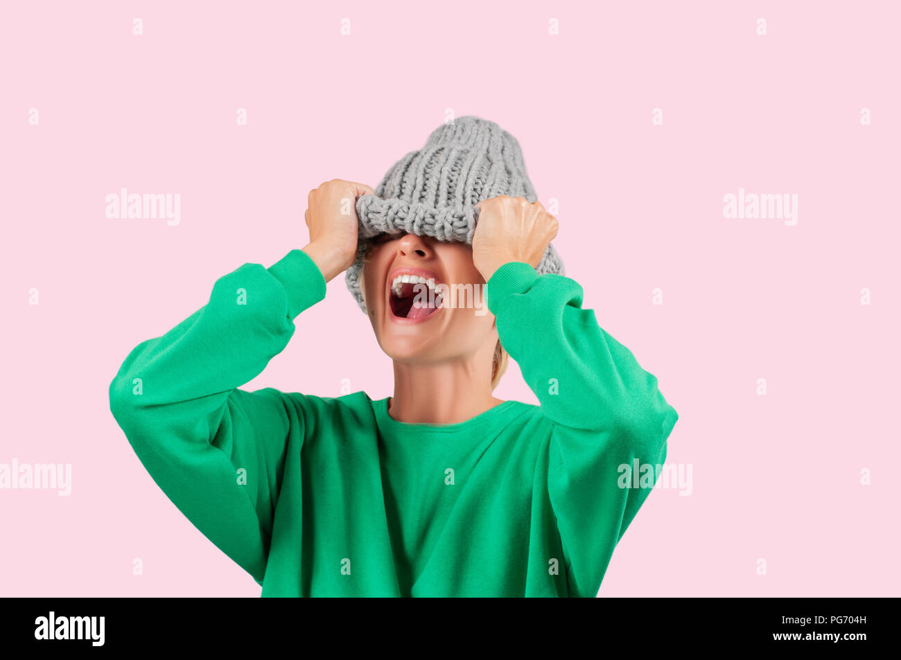 Furious. Emotional angry woman is pulling wool hat over her eyes on ...