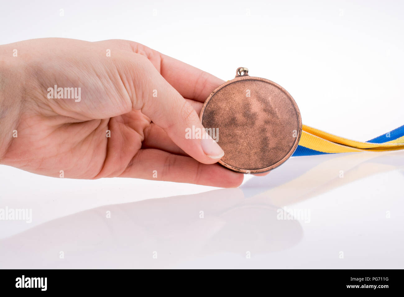 Hand holding a medal with blue and yellow ribbon Stock Photo - Alamy