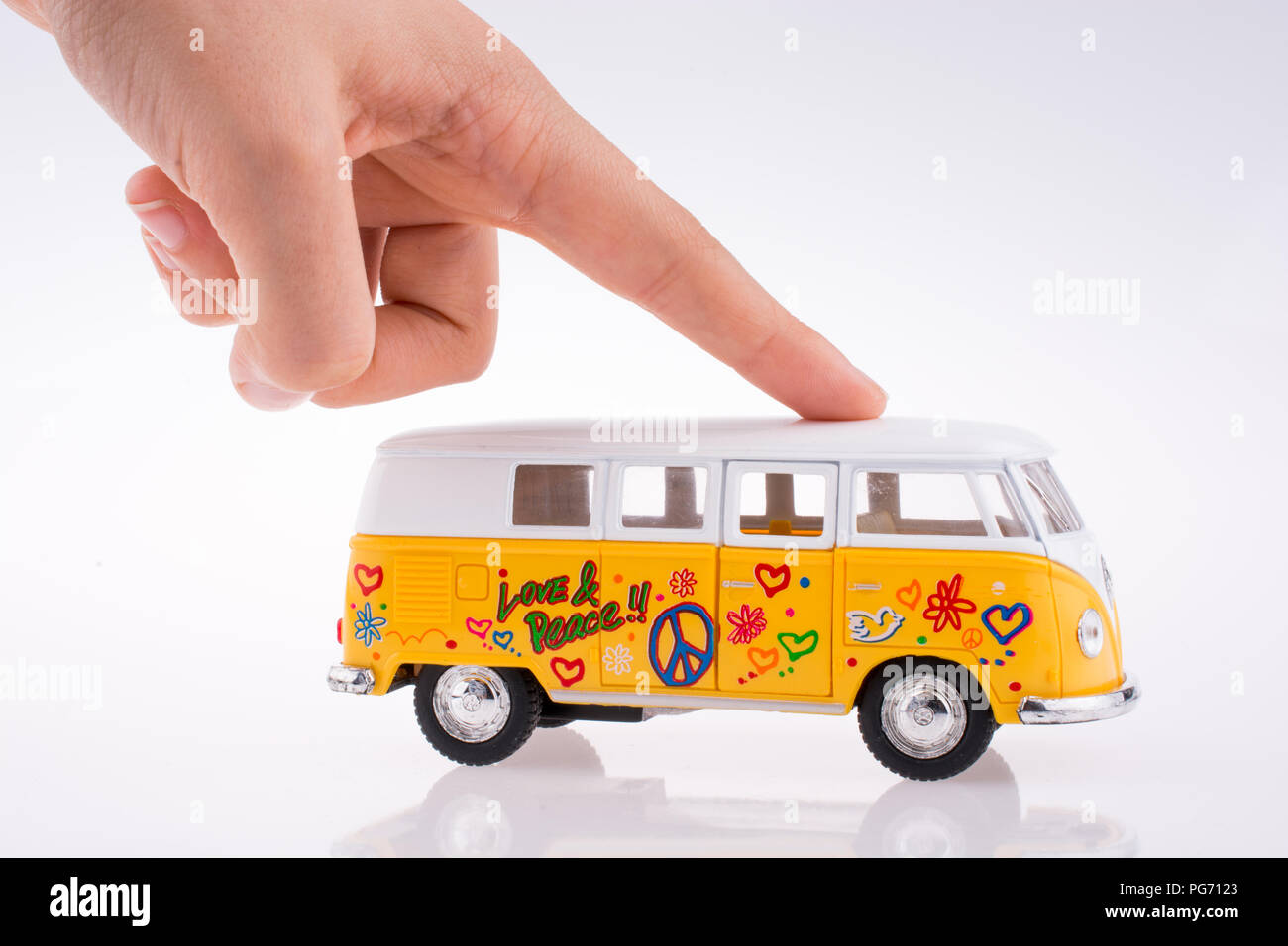 Hand holding a yellow Peace Van on a white background Stock Photo - Alamy