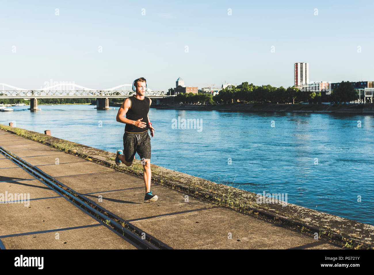 Young athlete jogging in the city at the river Stock Photo - Alamy