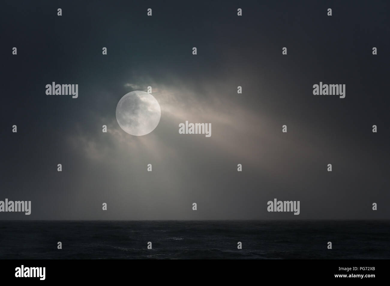Full moon over sea in an overcast night with moonbeams Stock Photo - Alamy