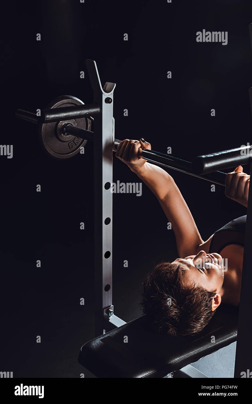 high angle view of female bodybuilder doing exercise with barbell at ...