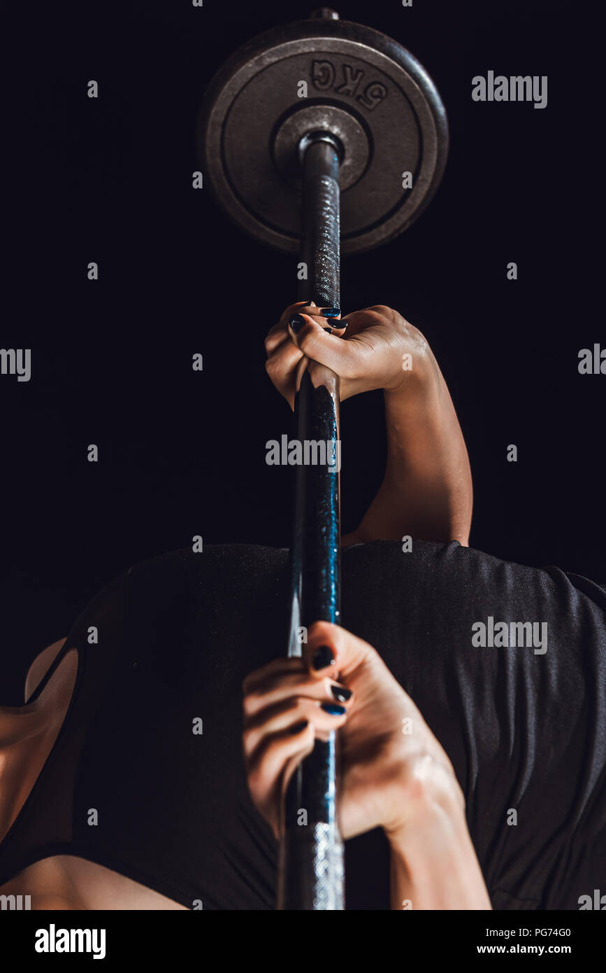 cropped image of female athlete doing exercise with barbell at gym ...