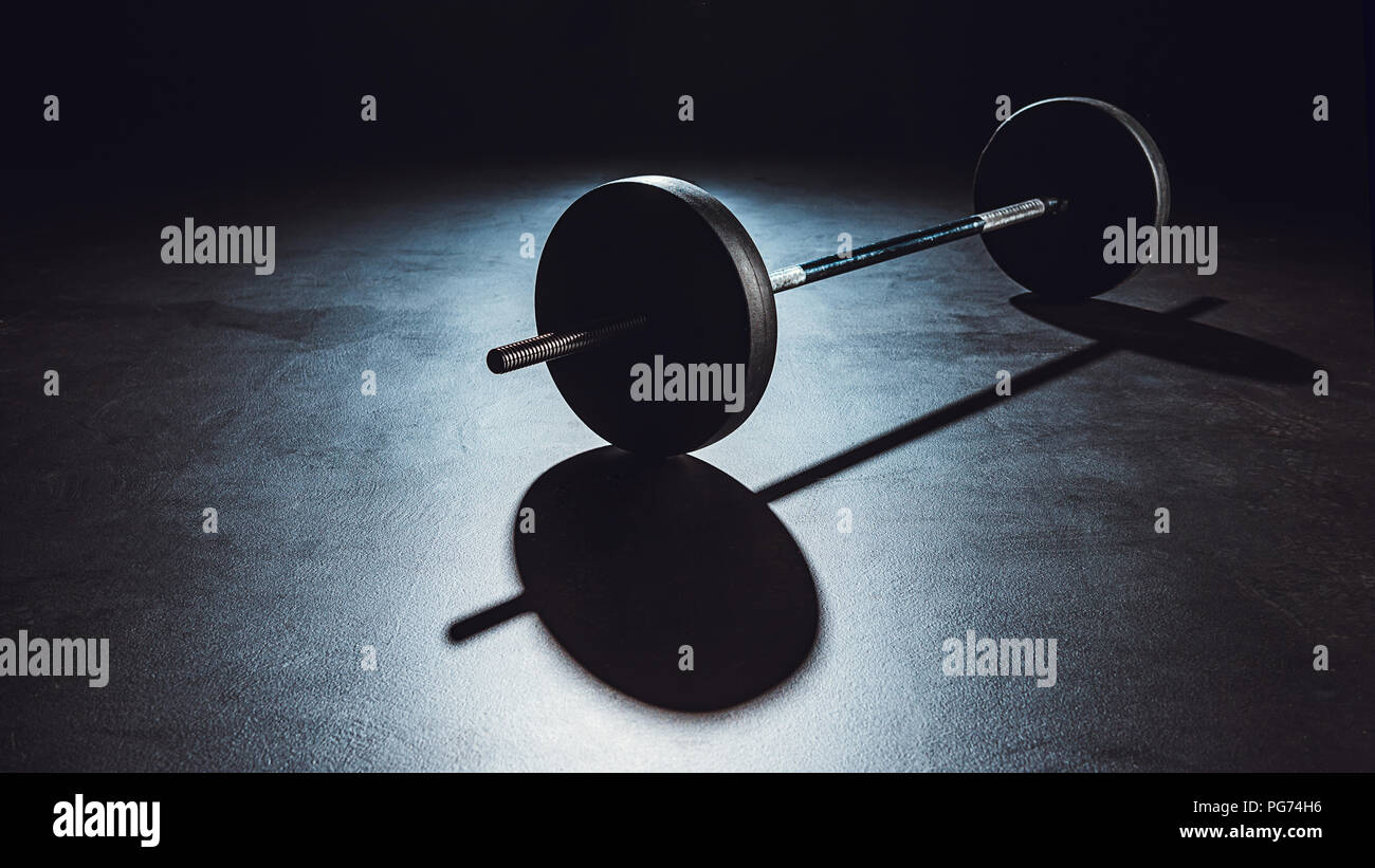 close up view of barbell on floor with shadow at gym, black background ...